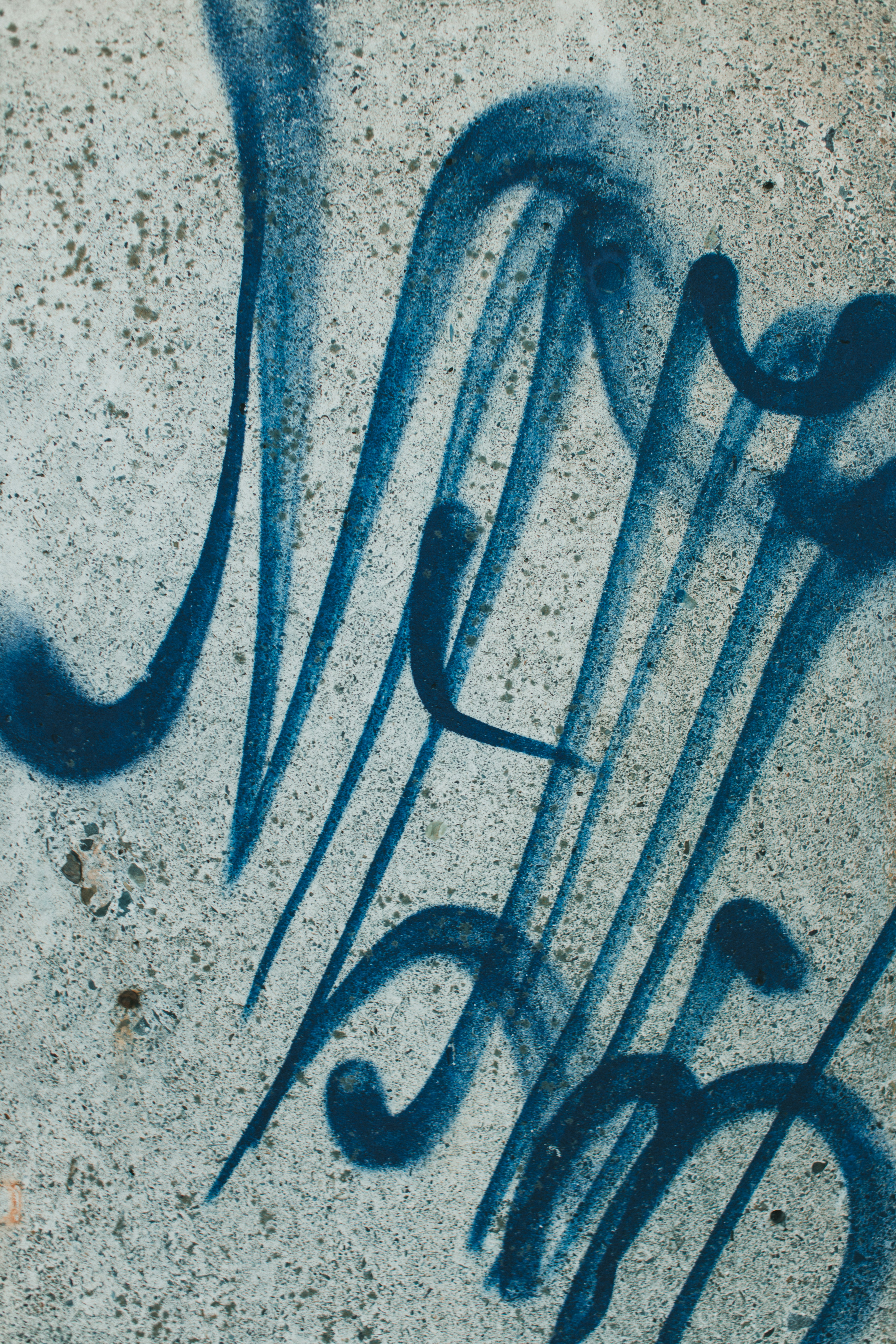 Abstract graffiti art featuring flowing blue lines on a textured concrete surface.