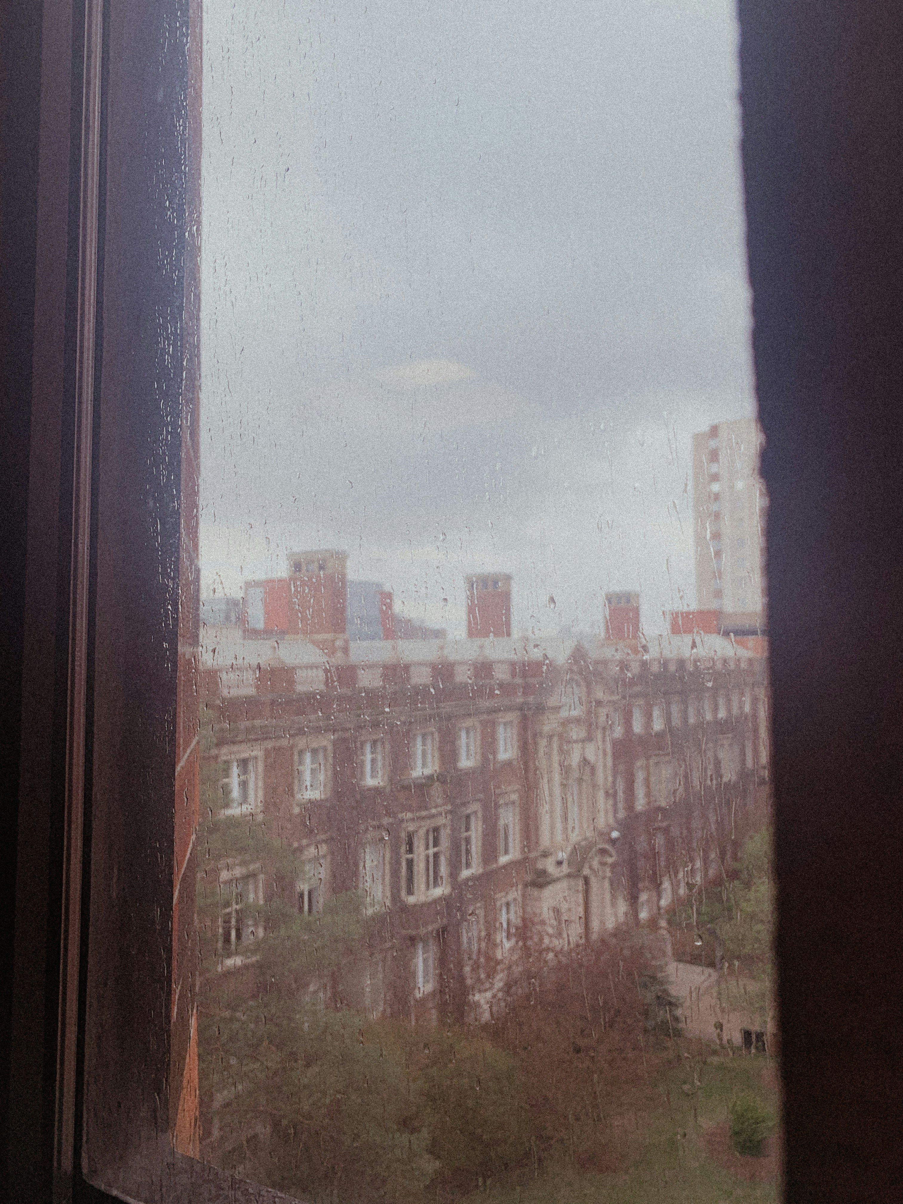 Rain-Kissed Brick Lane: Cityscape Through a Moist Window