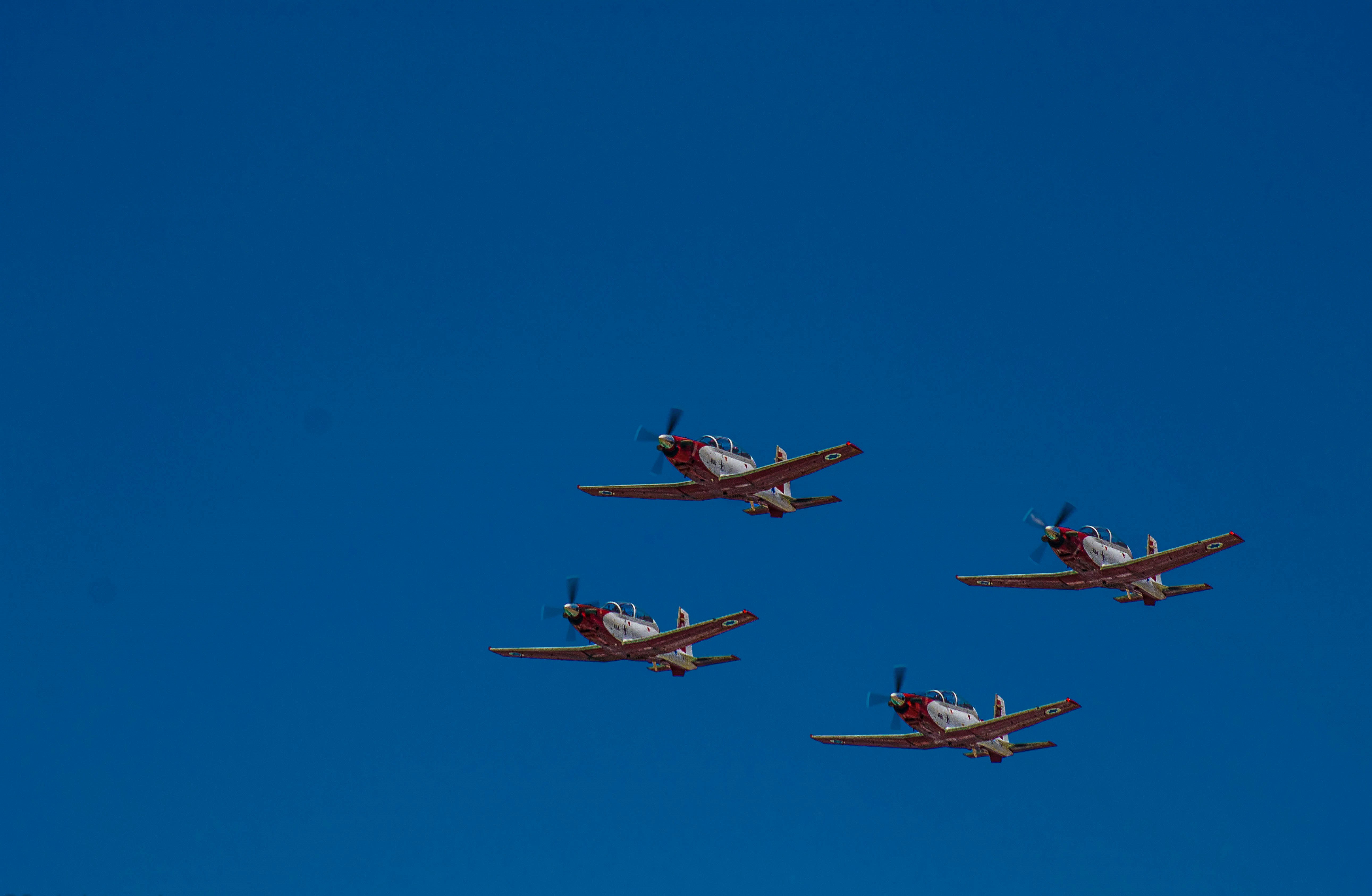 A group of four airplanes flying through a blue sky photo – Free ...