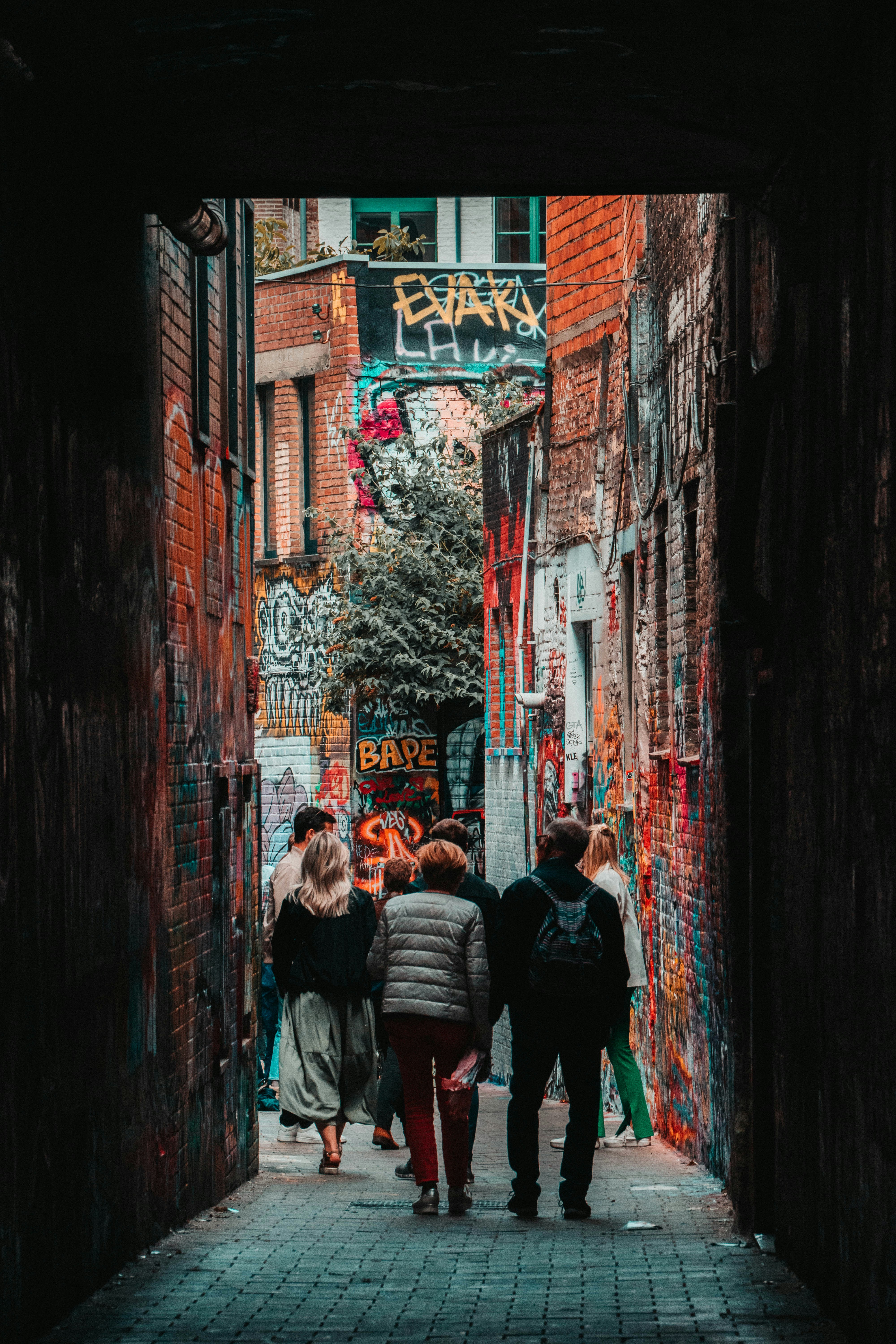 a group of people walking down a narrow alley way