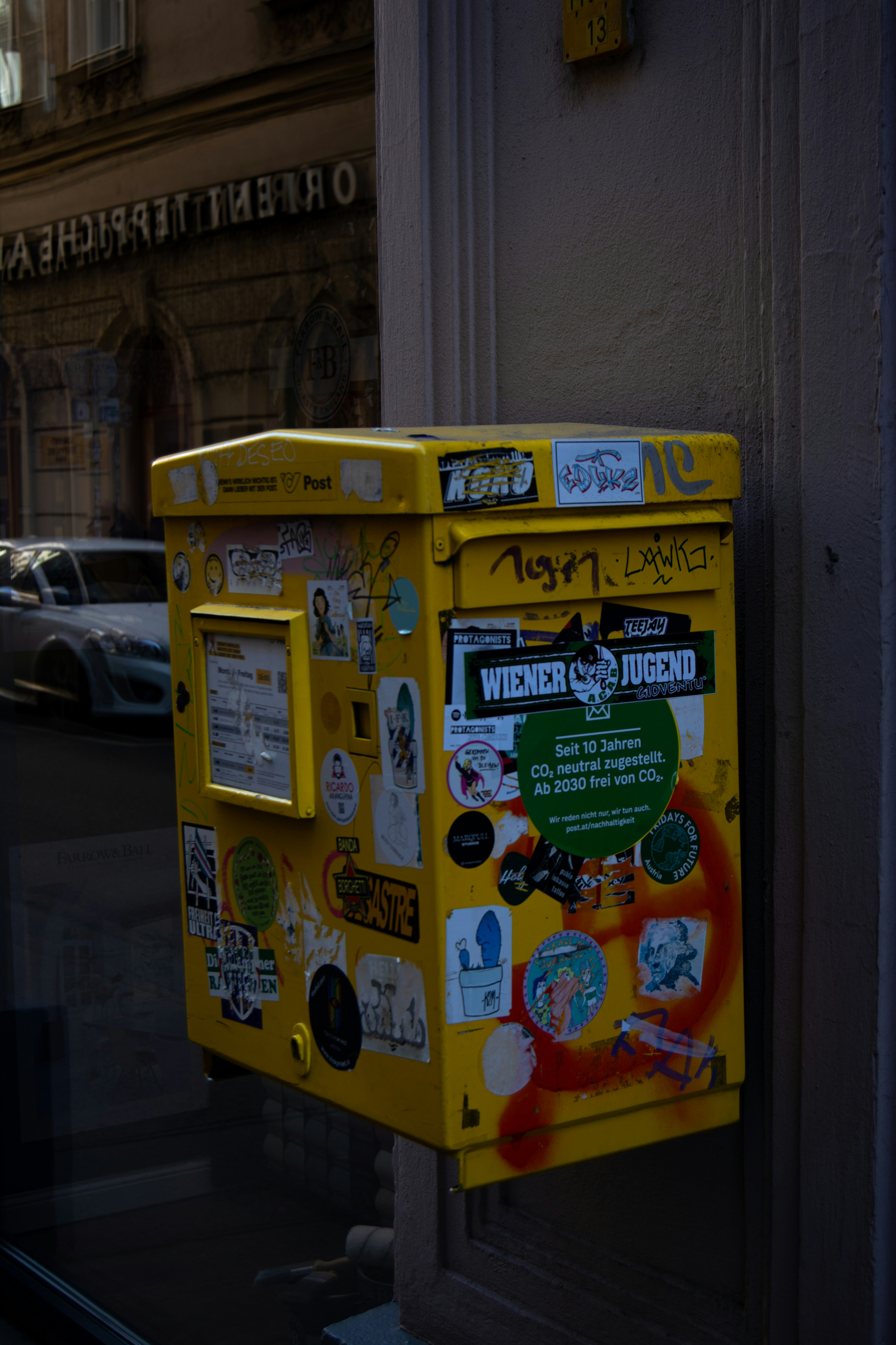 Stickered Yellow Mailbox at a Quiet Urban Corner