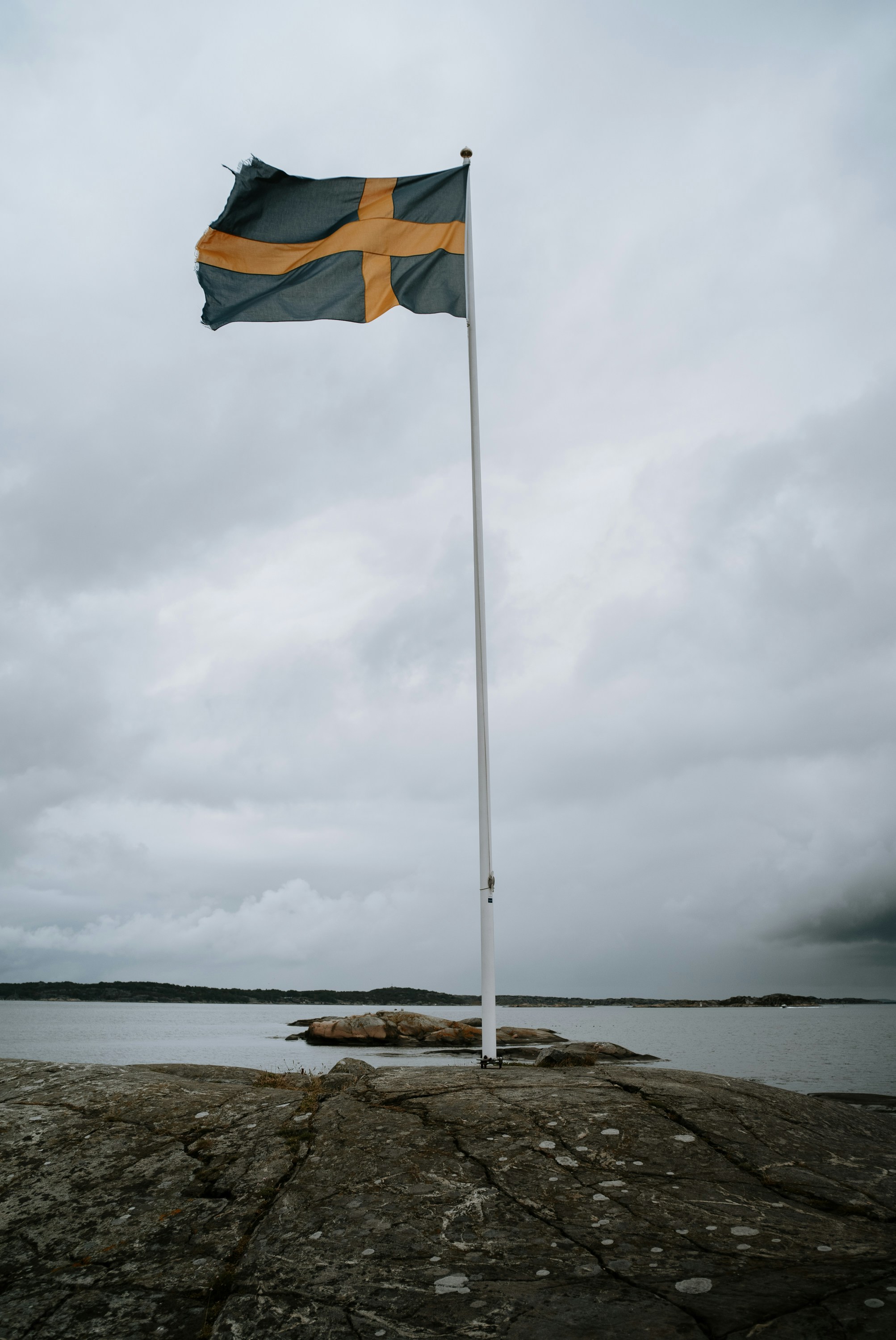 Una bandera en una roca junto al agua foto – Imagen de Gris gratuita en ...
