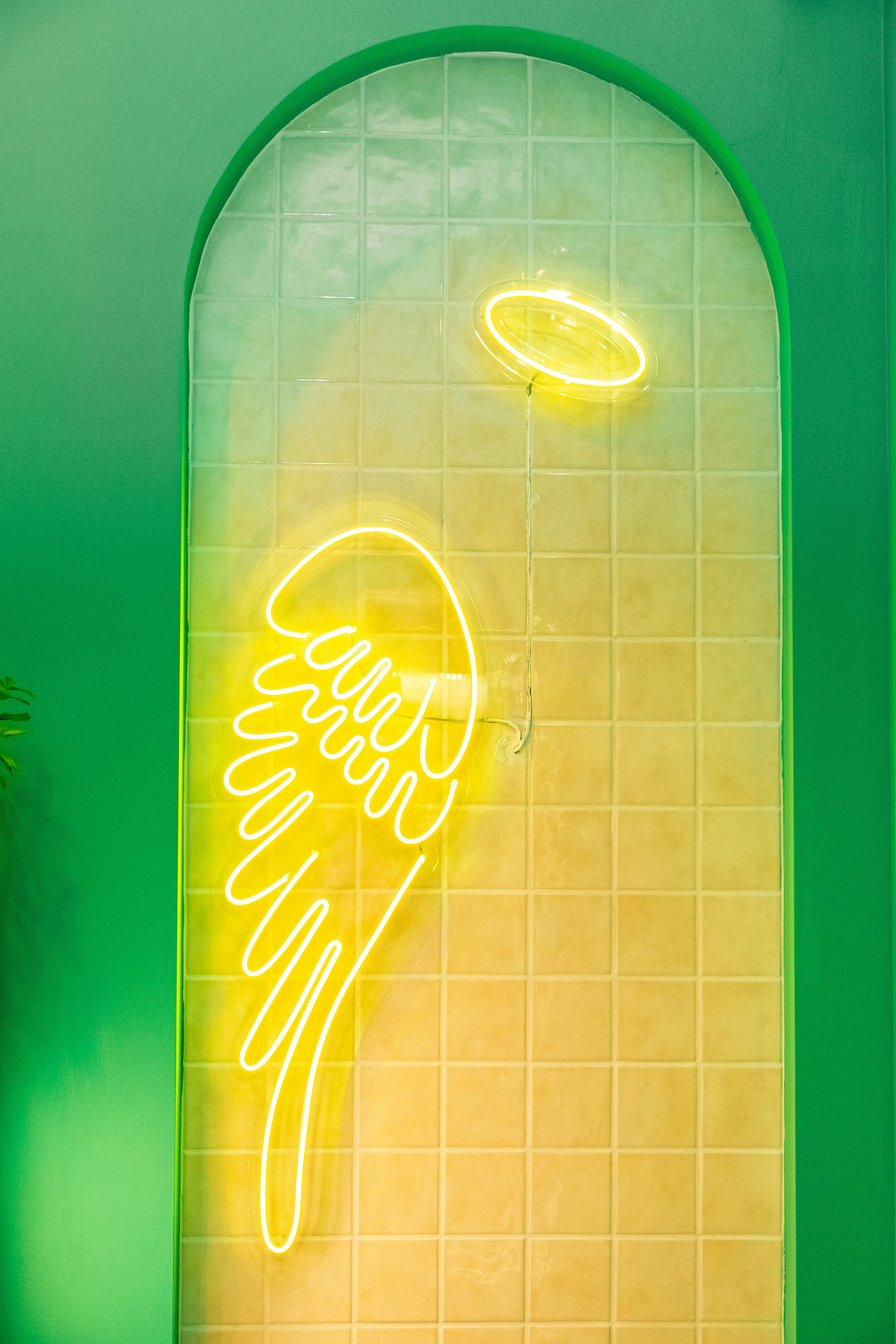 Lime Arch Neon: Halo and Angel Wing Illuminate a Quiet Green Wall