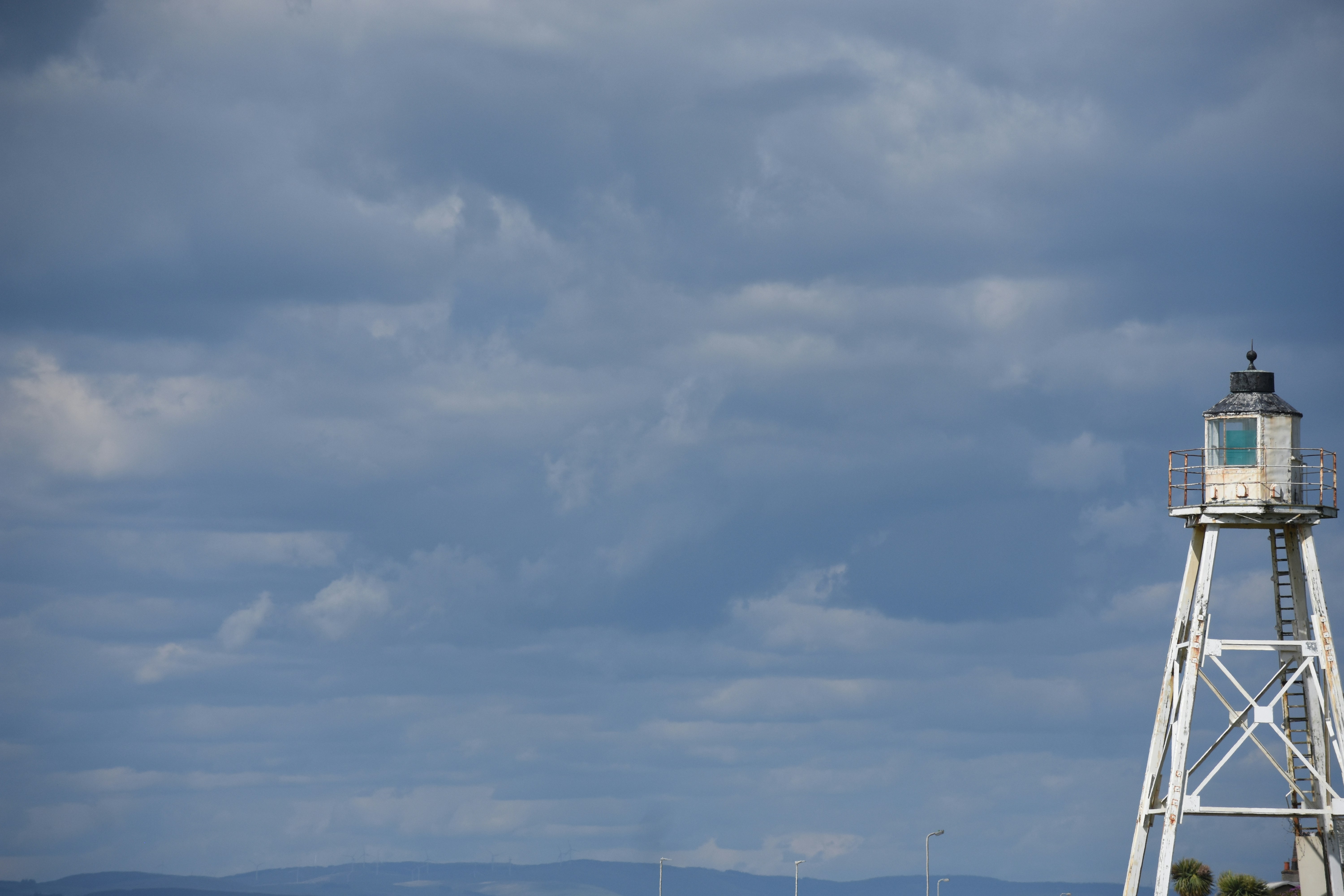 Beacon at the Edge: A Wind-Swept Lighthouse Against a Layered Sky