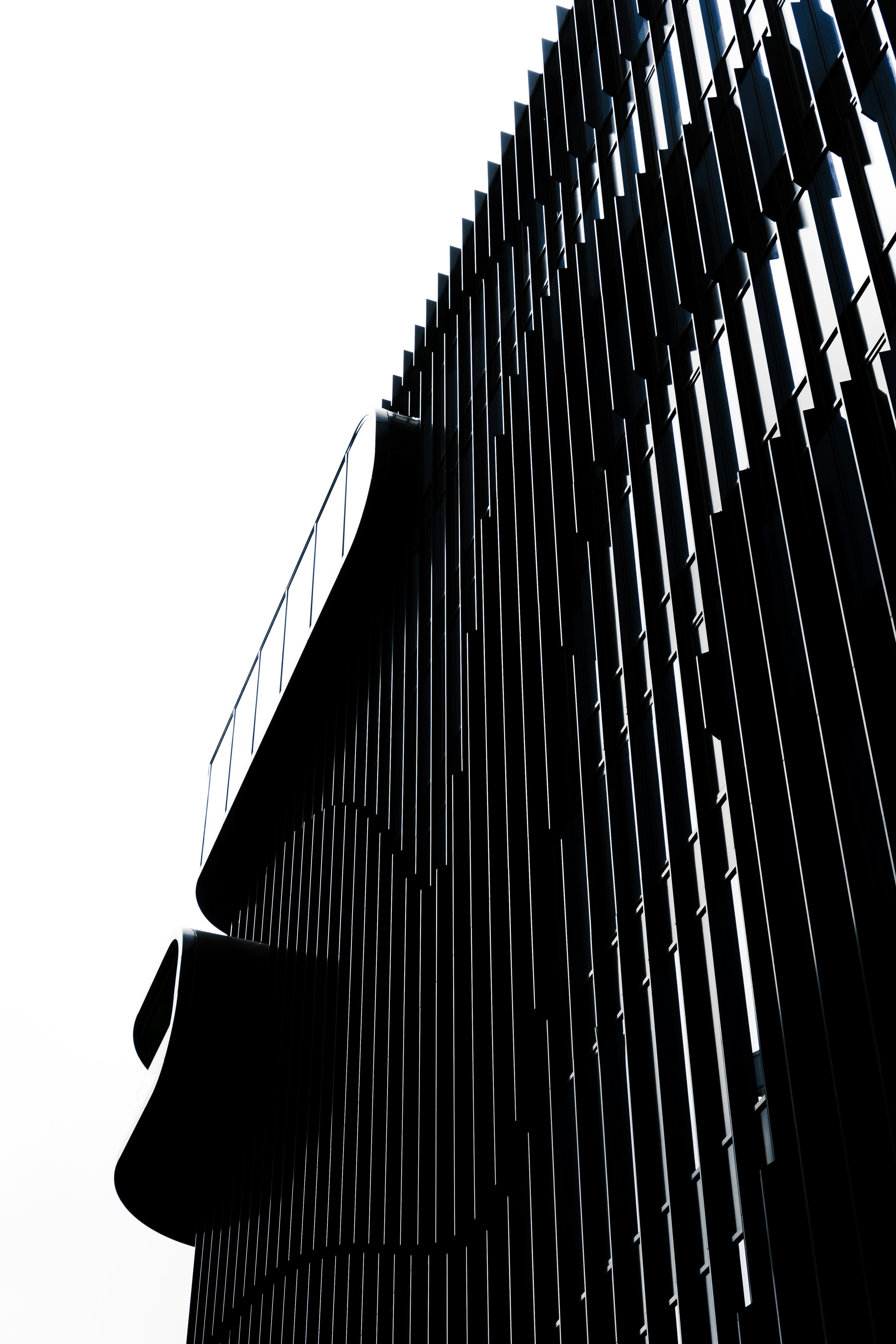 Abstract architectural facade showcasing a rhythmic pattern of vertical lines and smooth curves against a bright background.