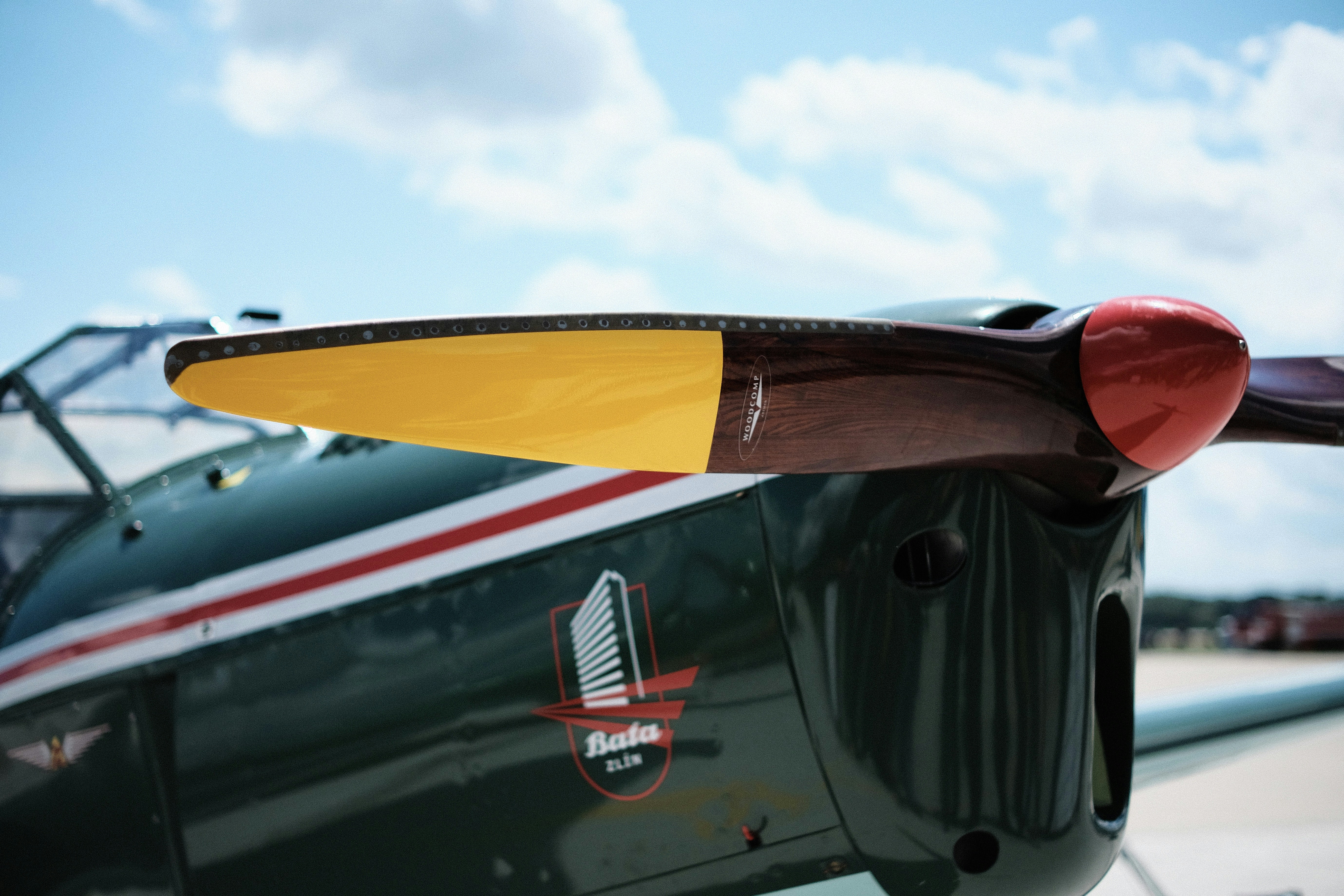 Green Skies, Red Spinner: A Close-Up of a Vintage Aircraft Propeller