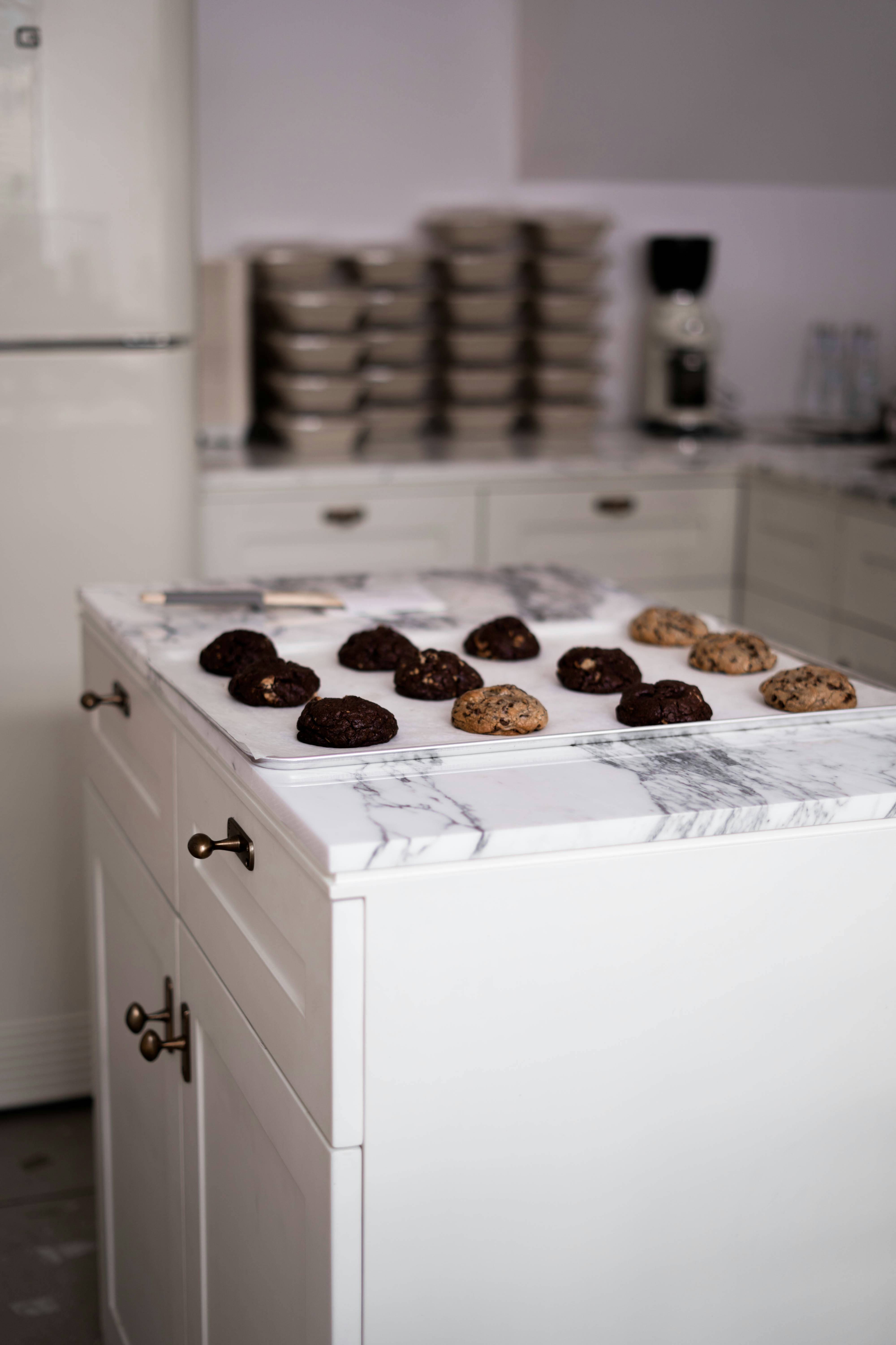 Freshly baked cookies arranged on a marble countertop in a modern kitchen setting.