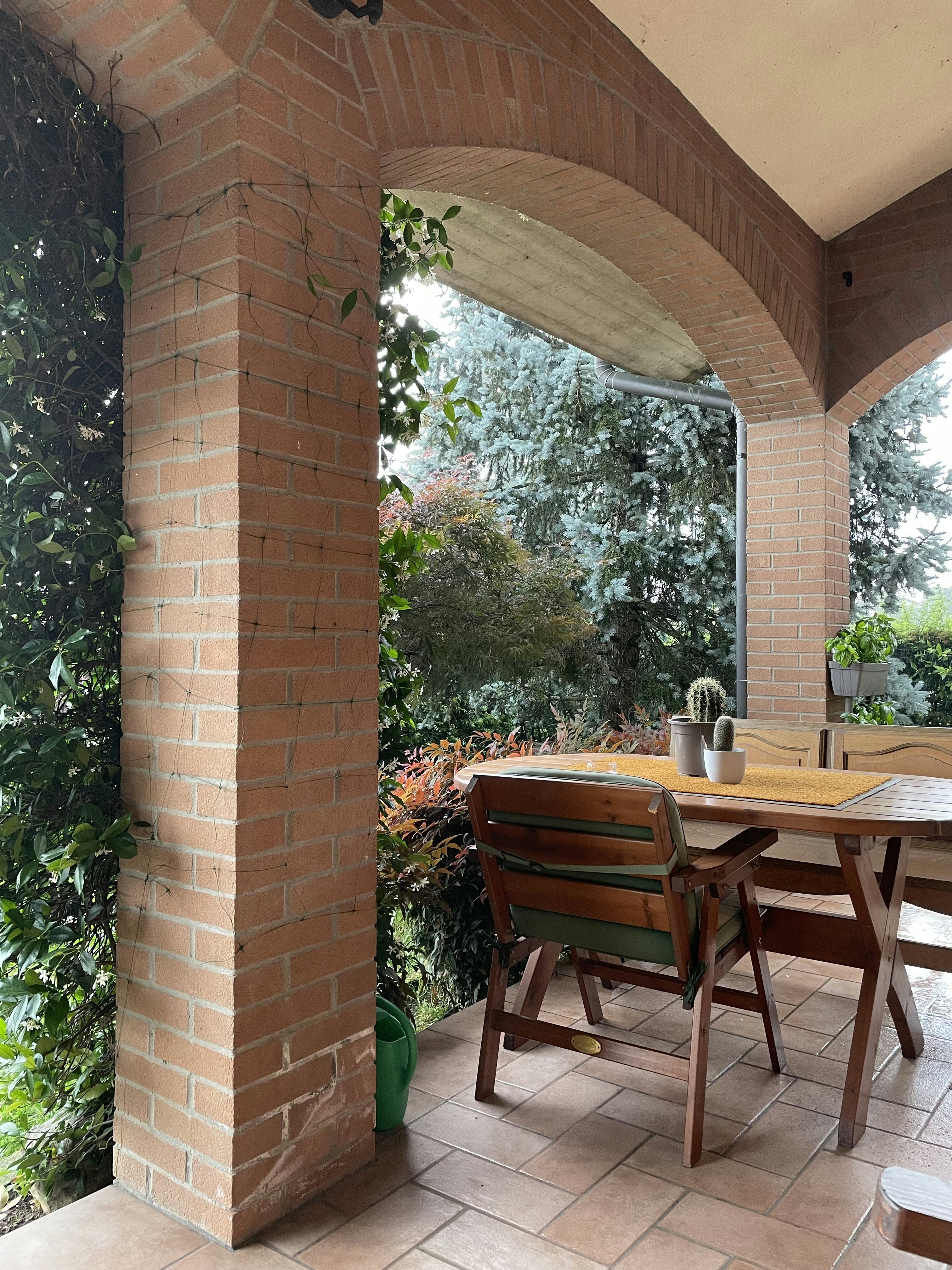 Brick Archway Terrace with Wood Table and Lush Garden View