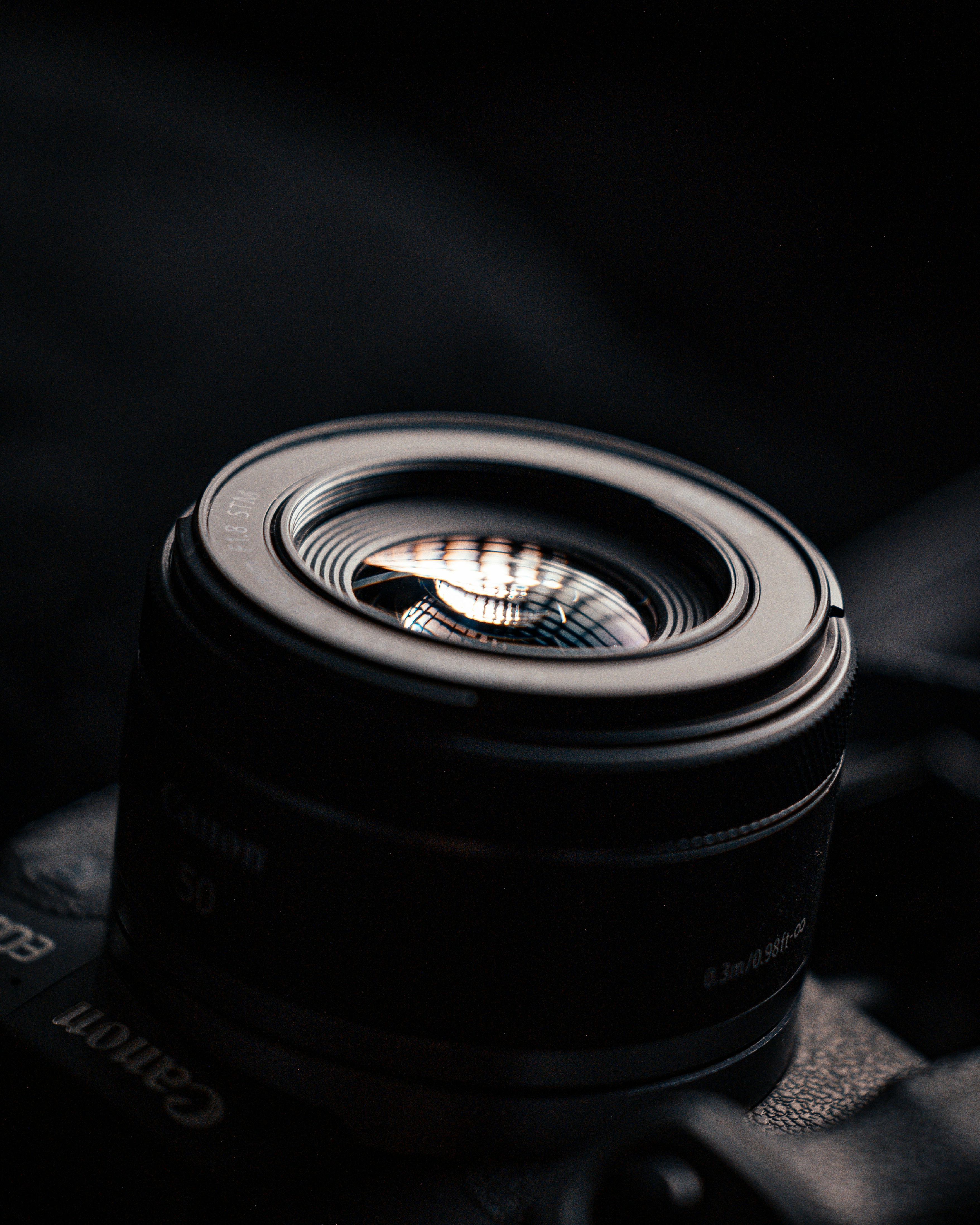 Close-up of a Canon lens showcasing intricate detailing and reflective elements. The image highlights the craftsmanship of camera equipment.