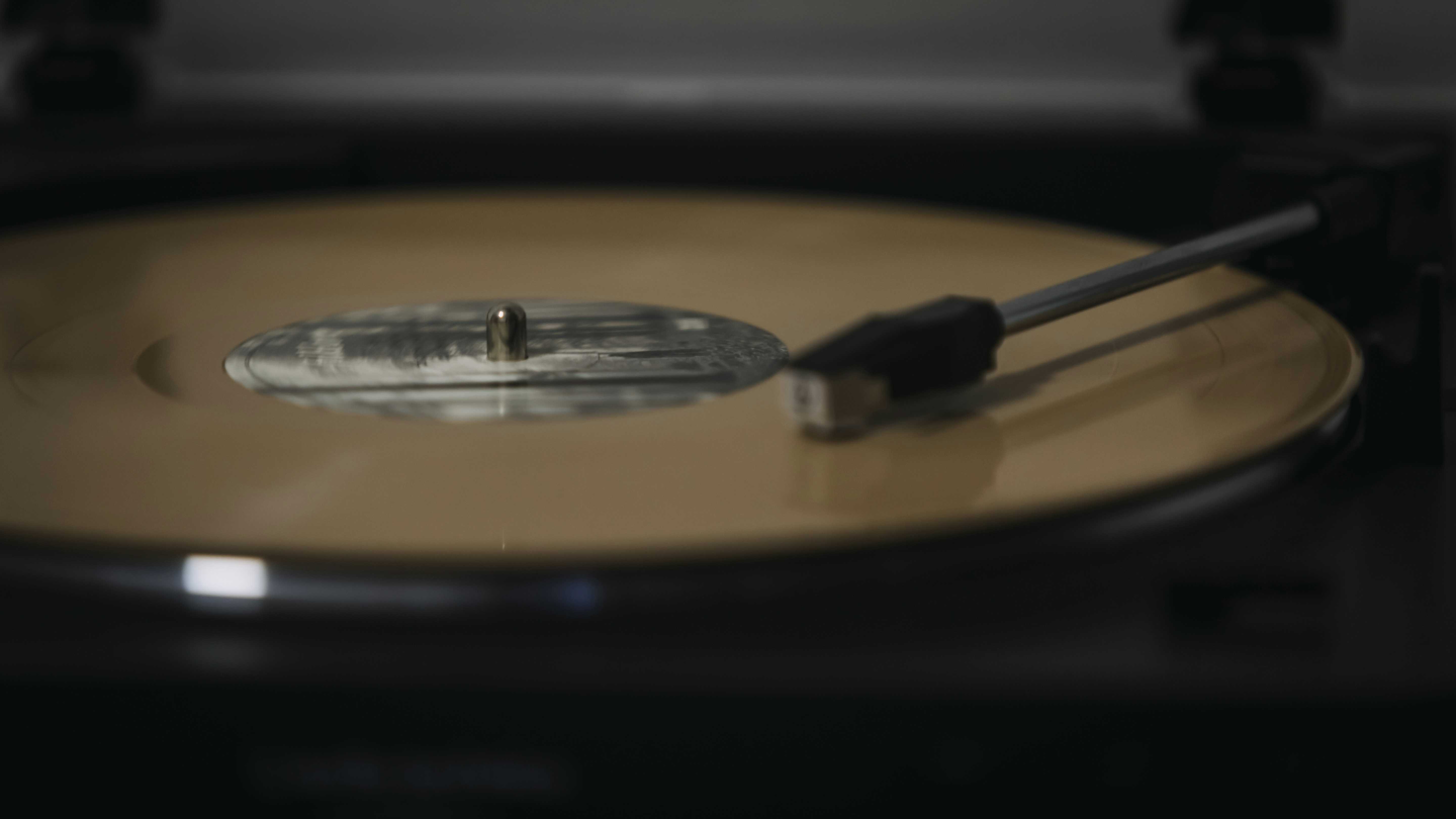 A close-up of a golden vinyl record spinning on a turntable, with the needle poised to capture the music. The scene evokes a sense of nostalgia and warmth.