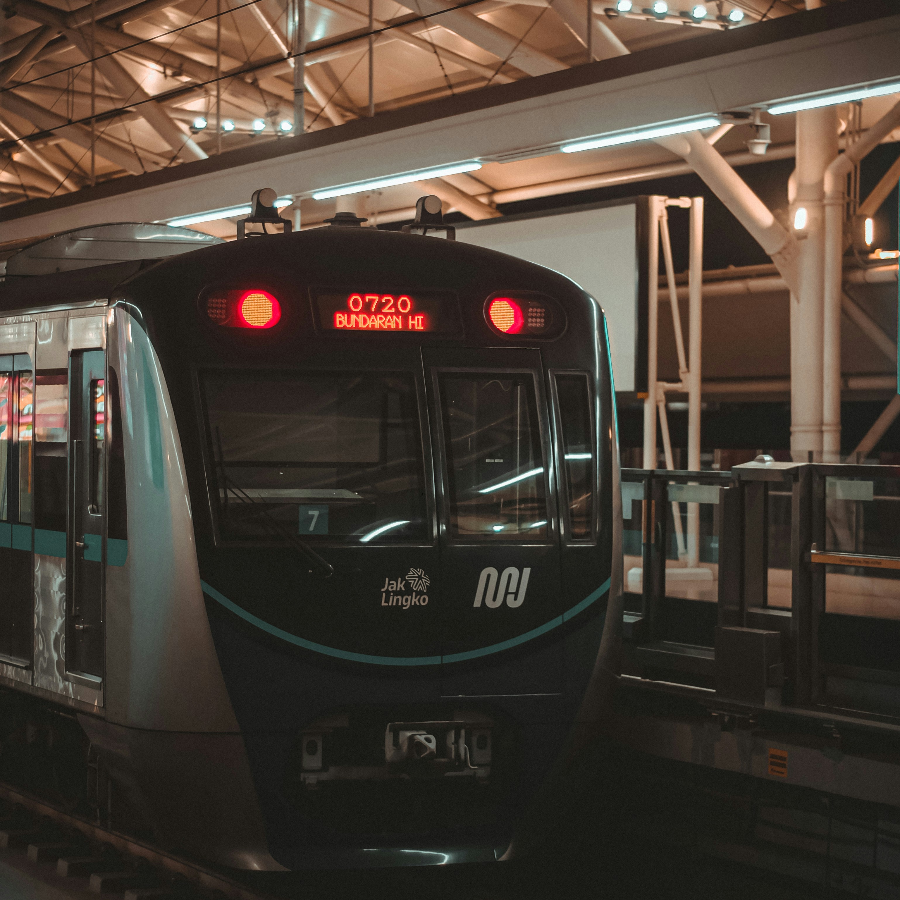 Train at a modern station illuminated by soft lights, showcasing its destination and sleek design.