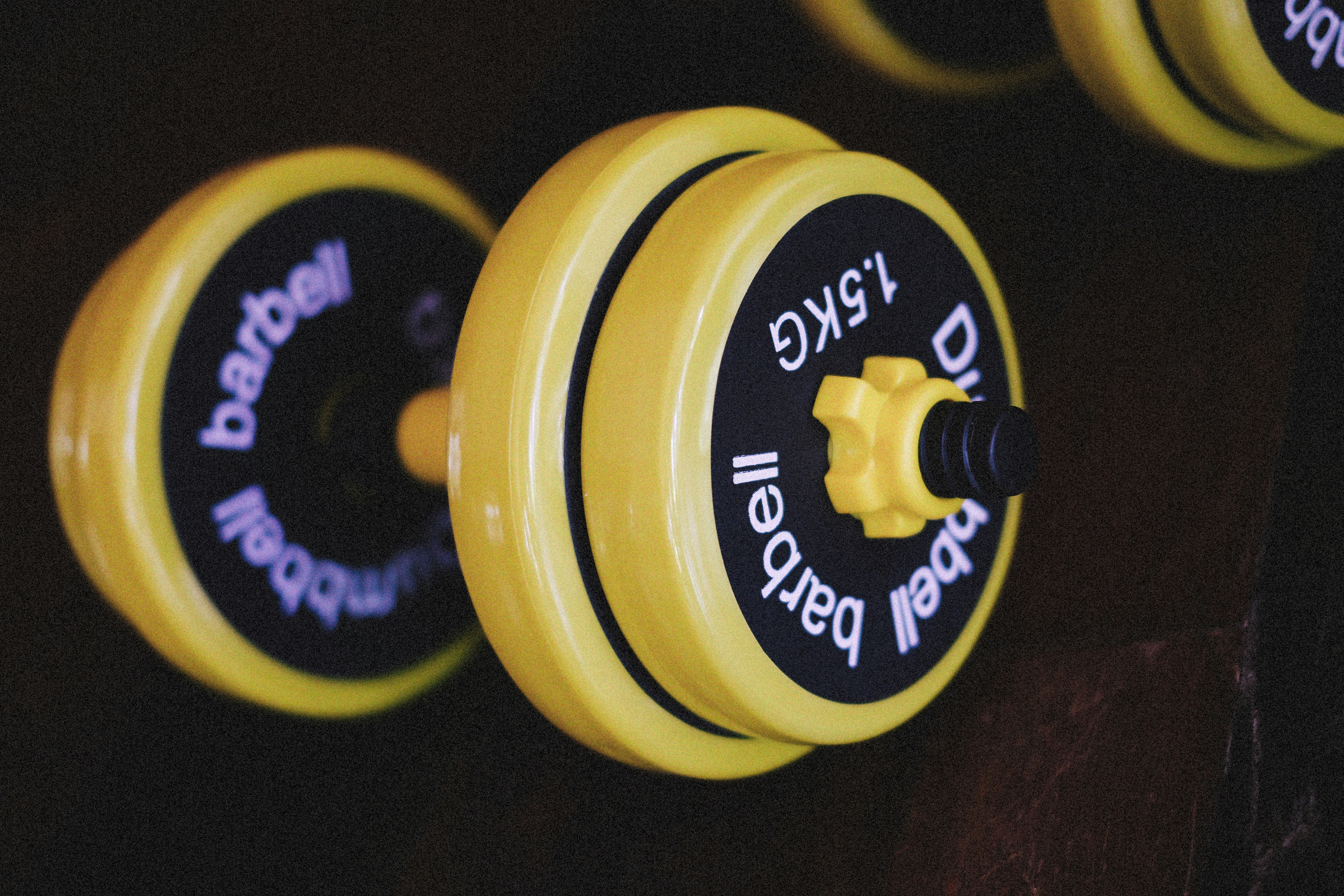 Close-Up of Yellow Weight Plates with Black Center on a Dark Bench