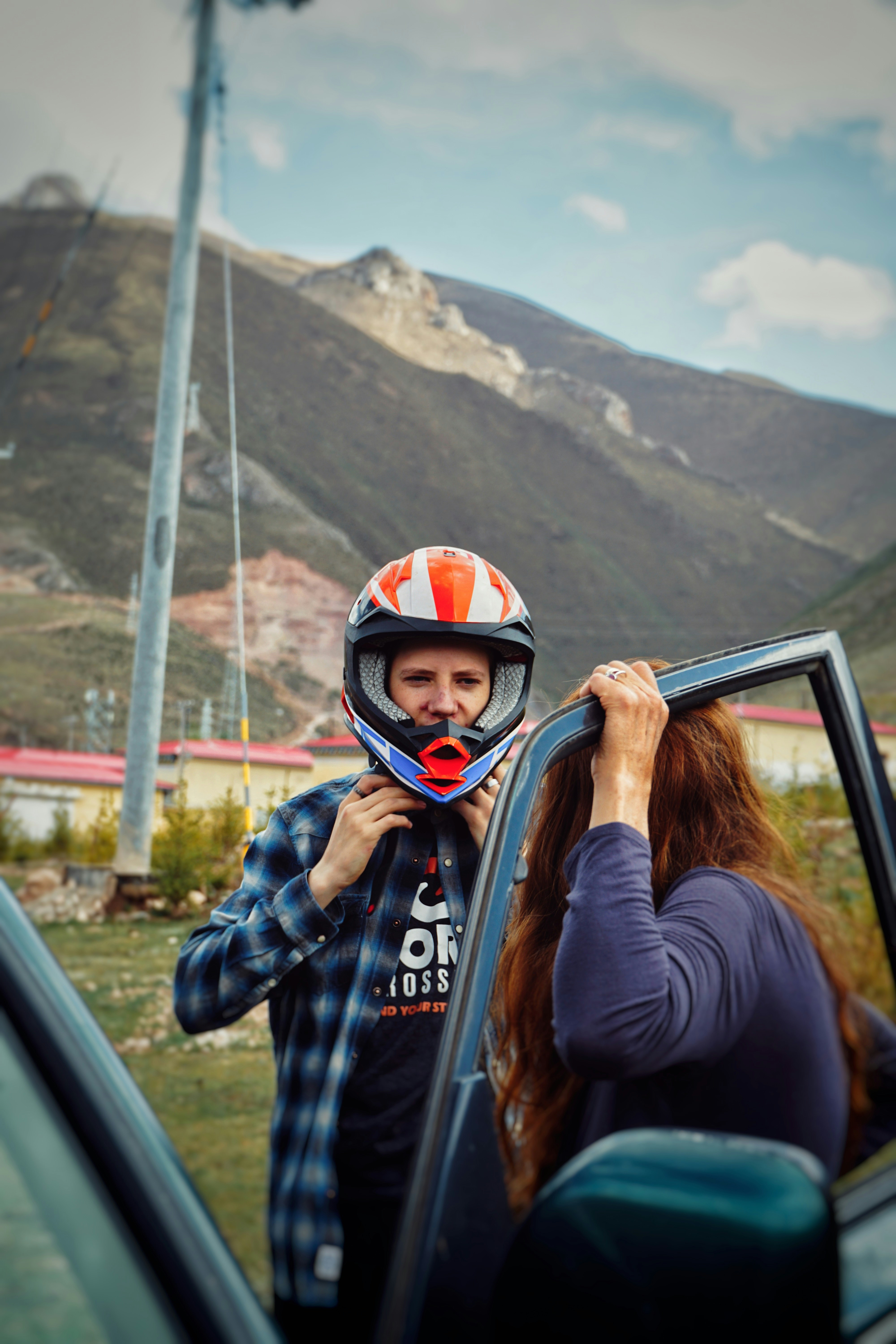 a man putting on a helmet next to a woman in a car