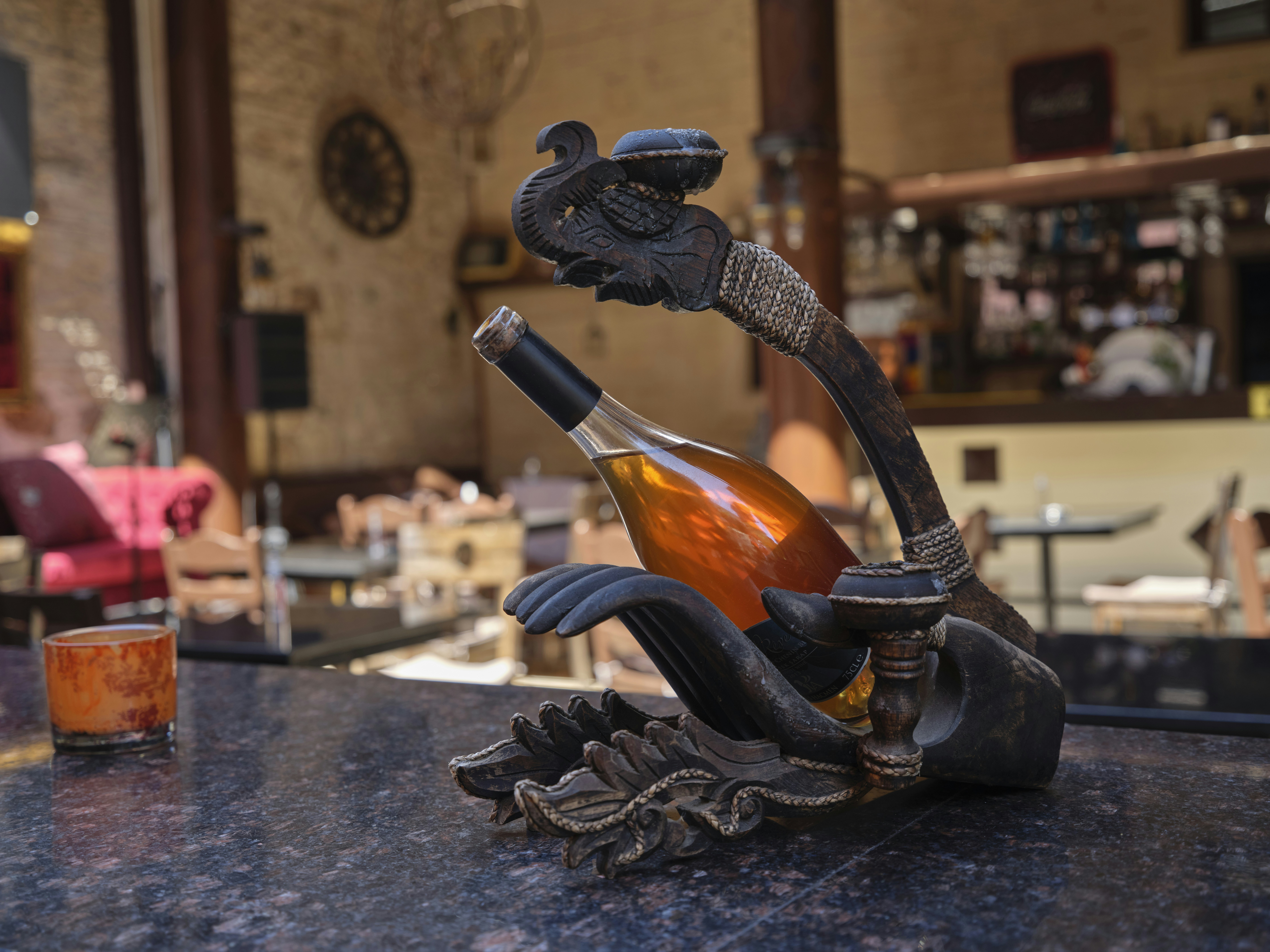Dragon-Head Wine Stand Framing Amber Bottle on a Weathered Tavern Table