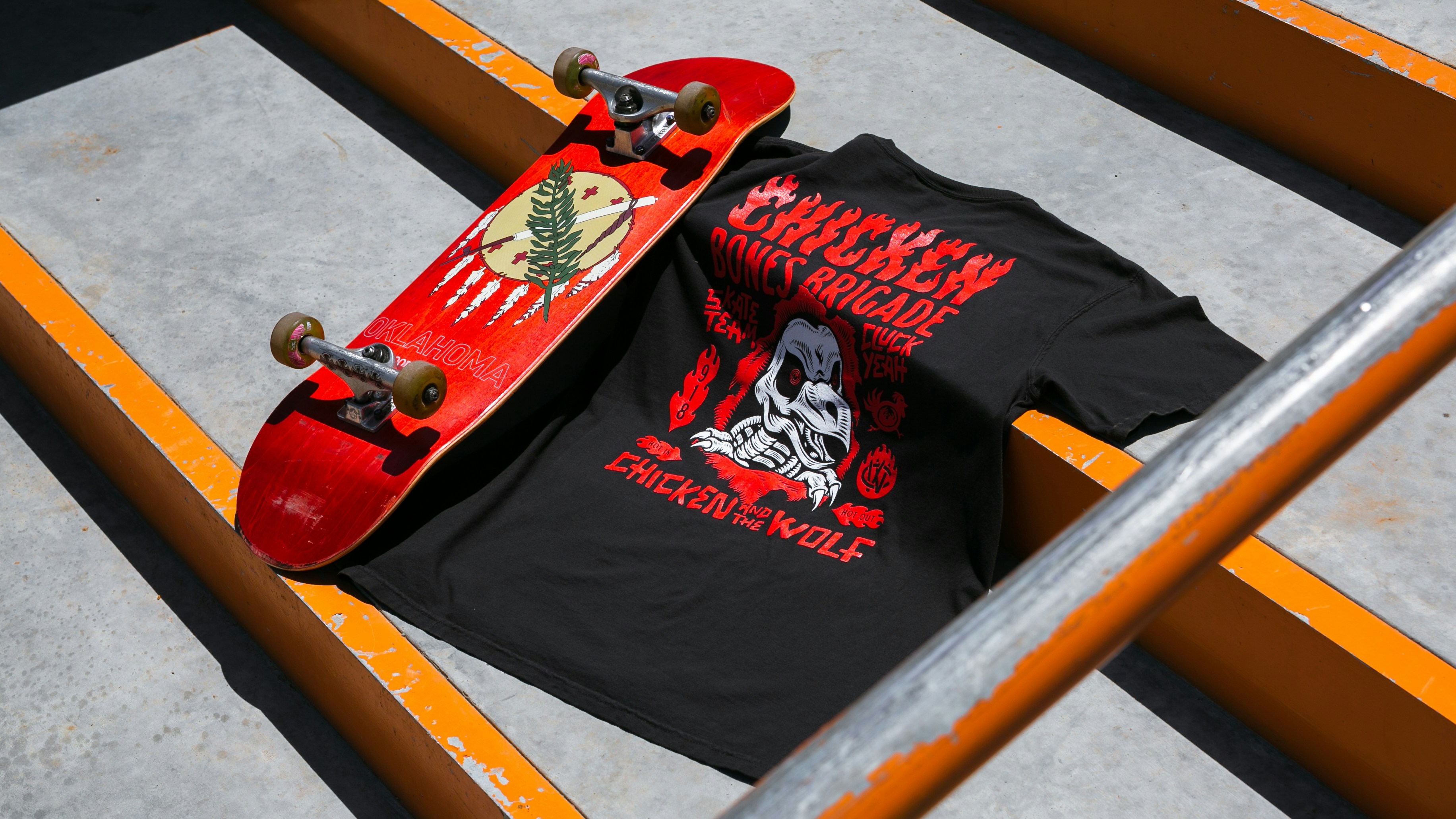 Red skateboard and graphic tee nestled in a sunlit skatepark frame