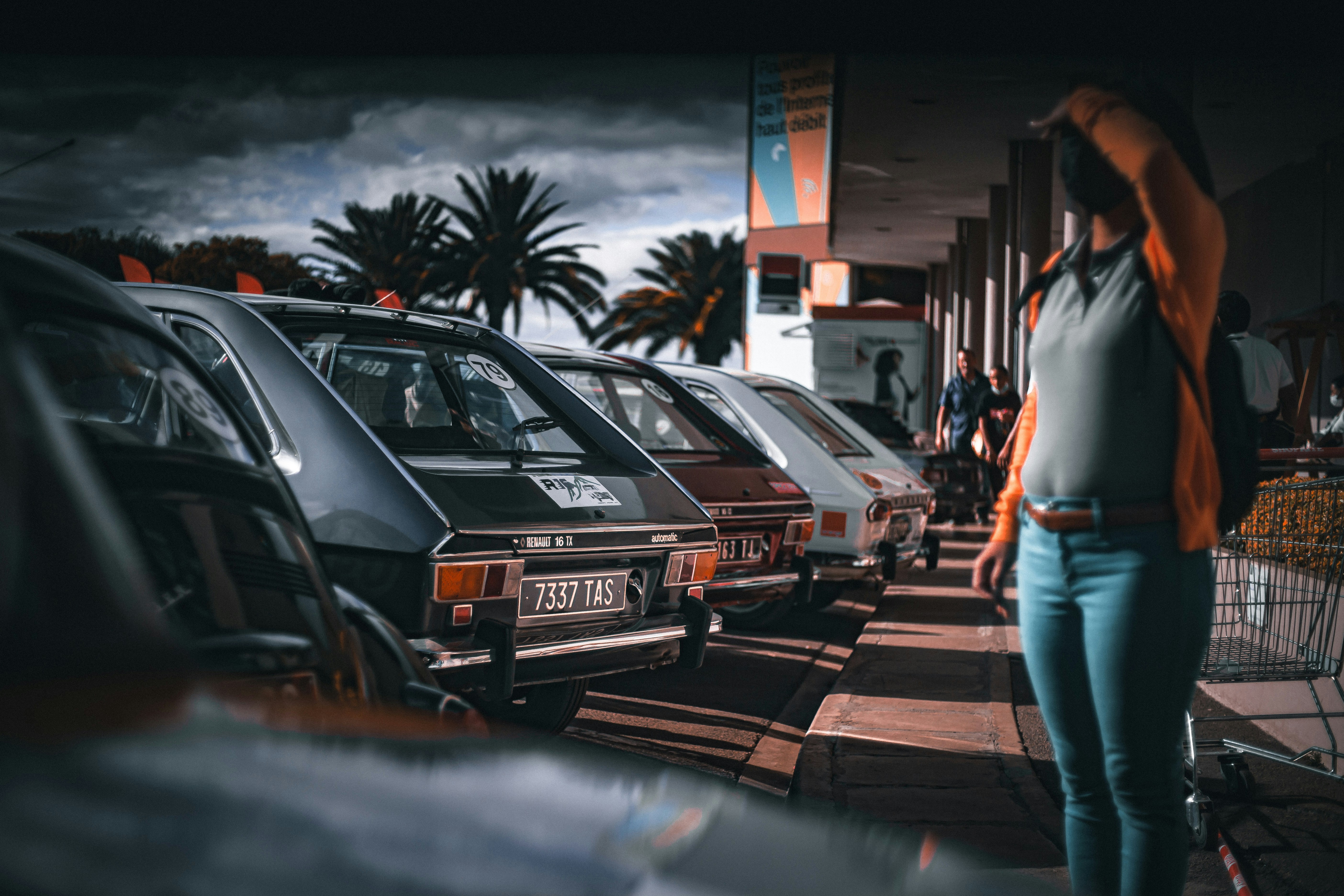 a woman standing next to a row of parked cars
