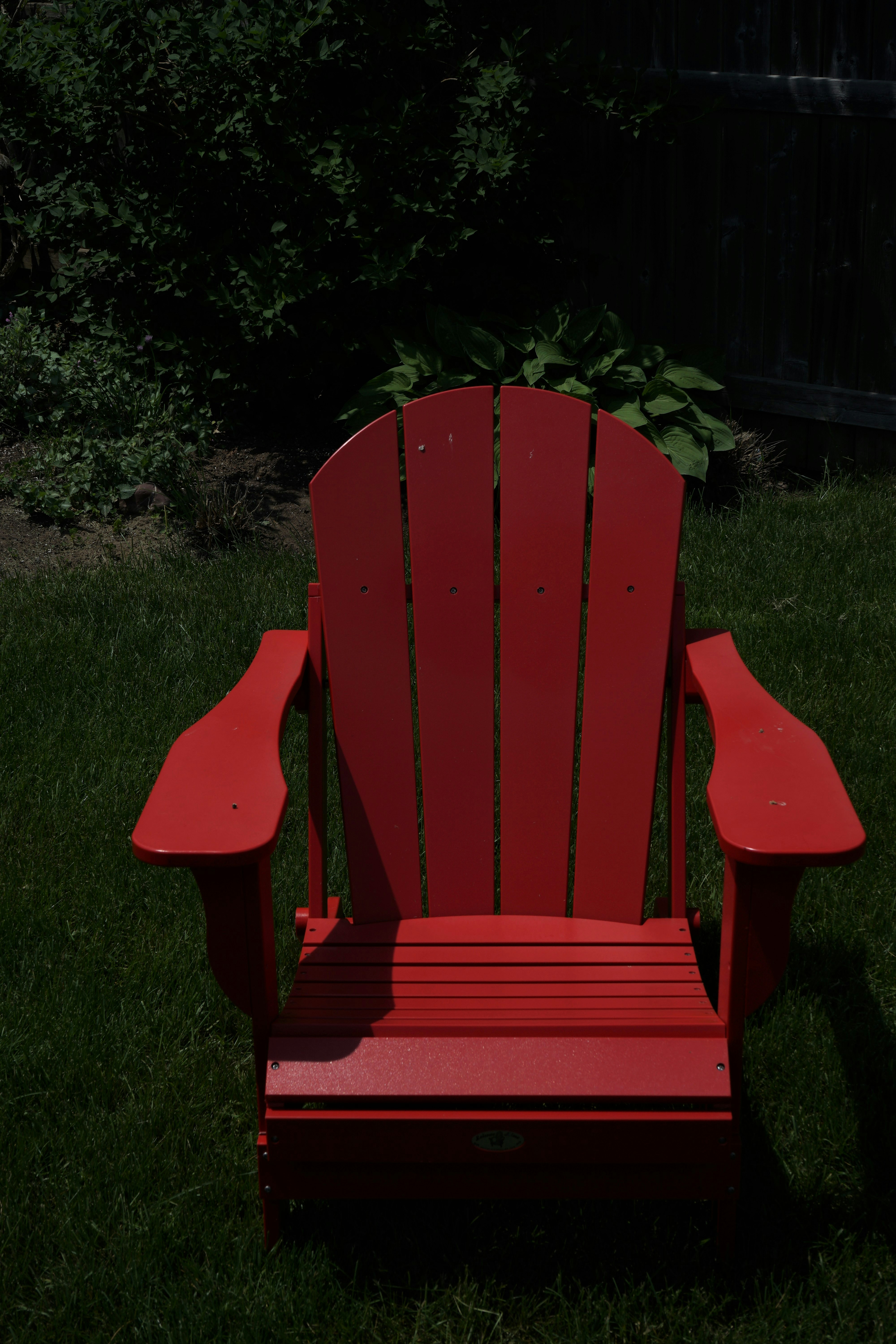 Red Adirondack Chair Standing Alone in a Shaded Garden