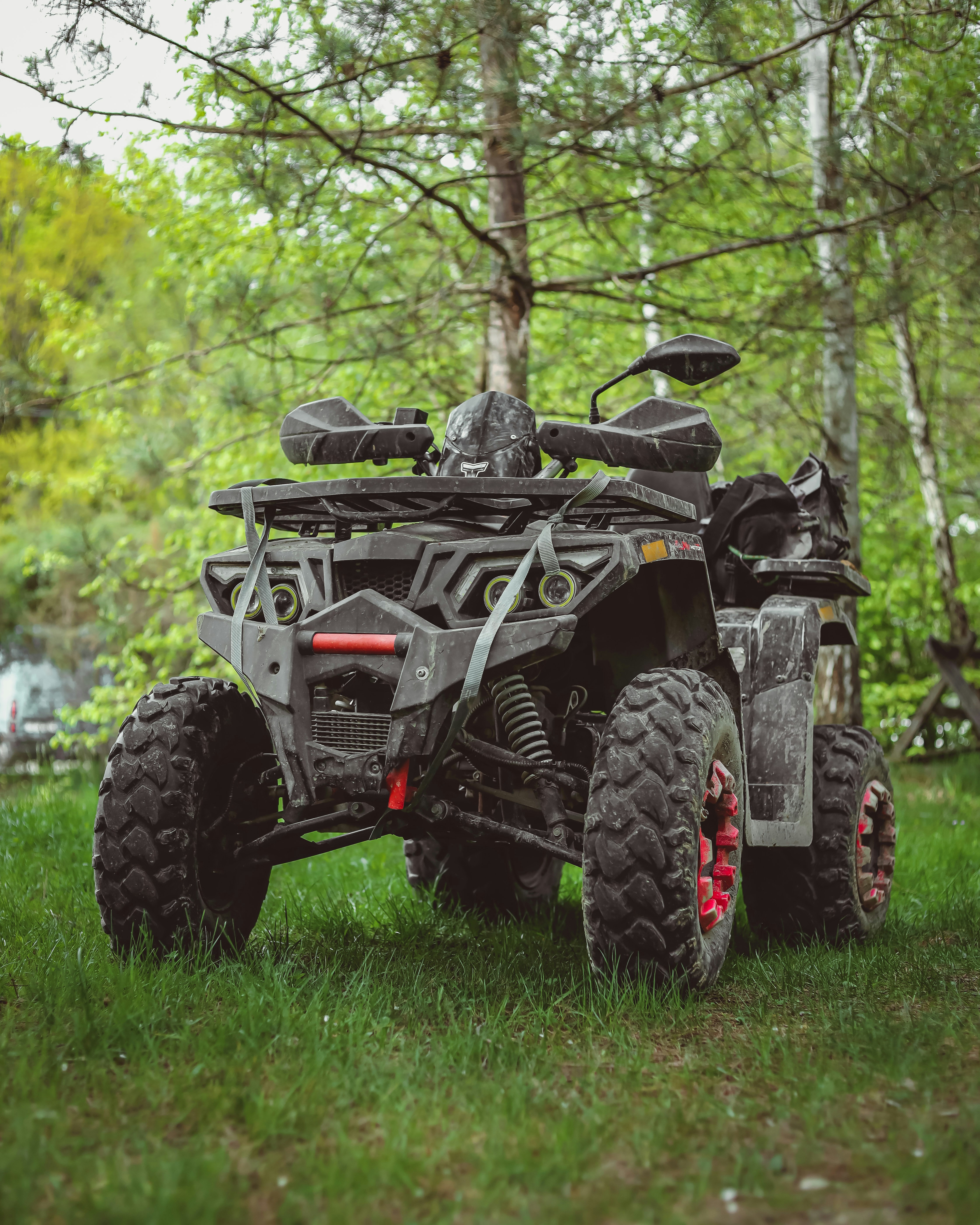 All-terrain vehicle parked amidst lush greenery, showcasing its robust design and rugged tires. The scene conveys a sense of outdoor adventure.