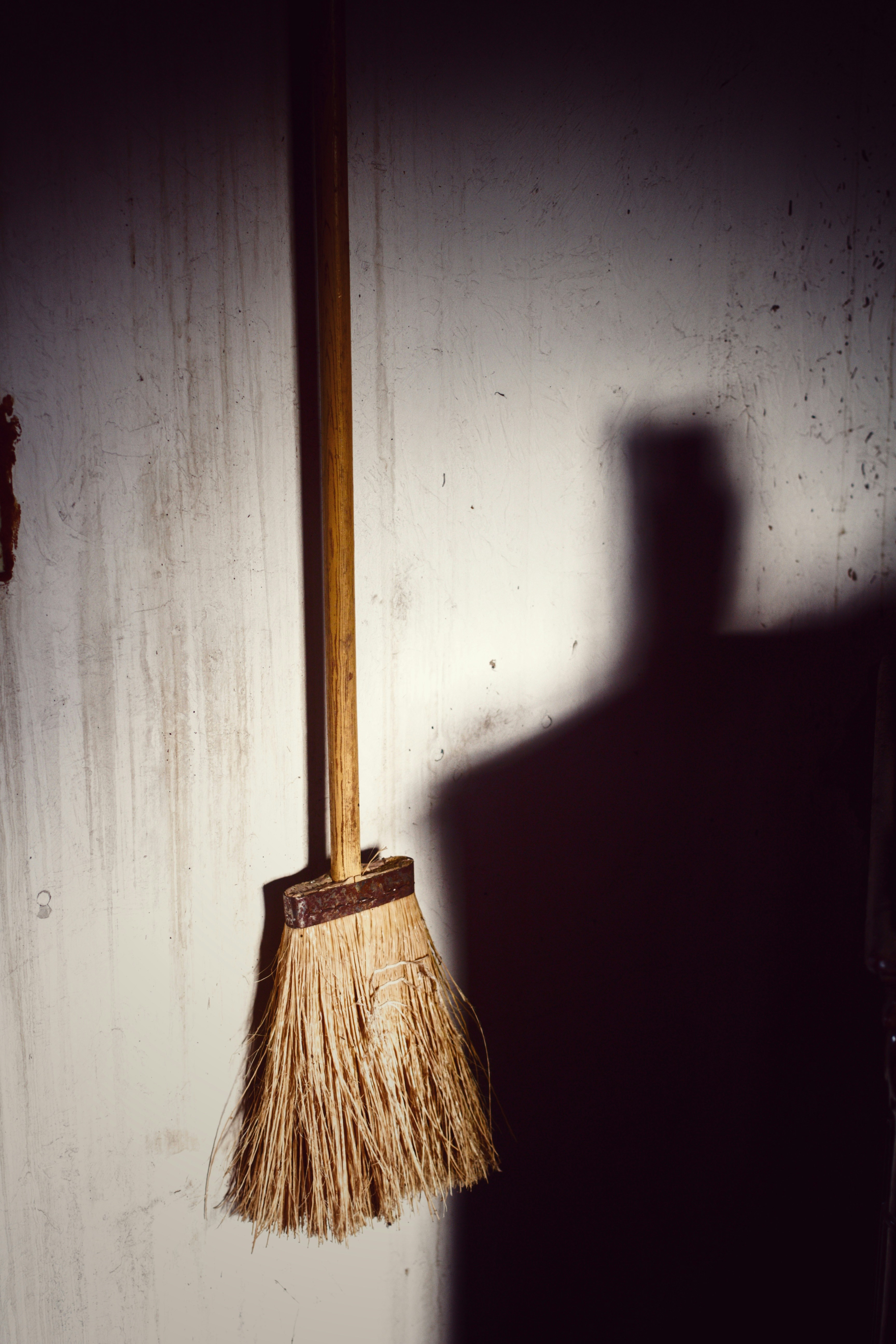 A broom leaning against a wall with a shadow on it photo – Free Beige ...