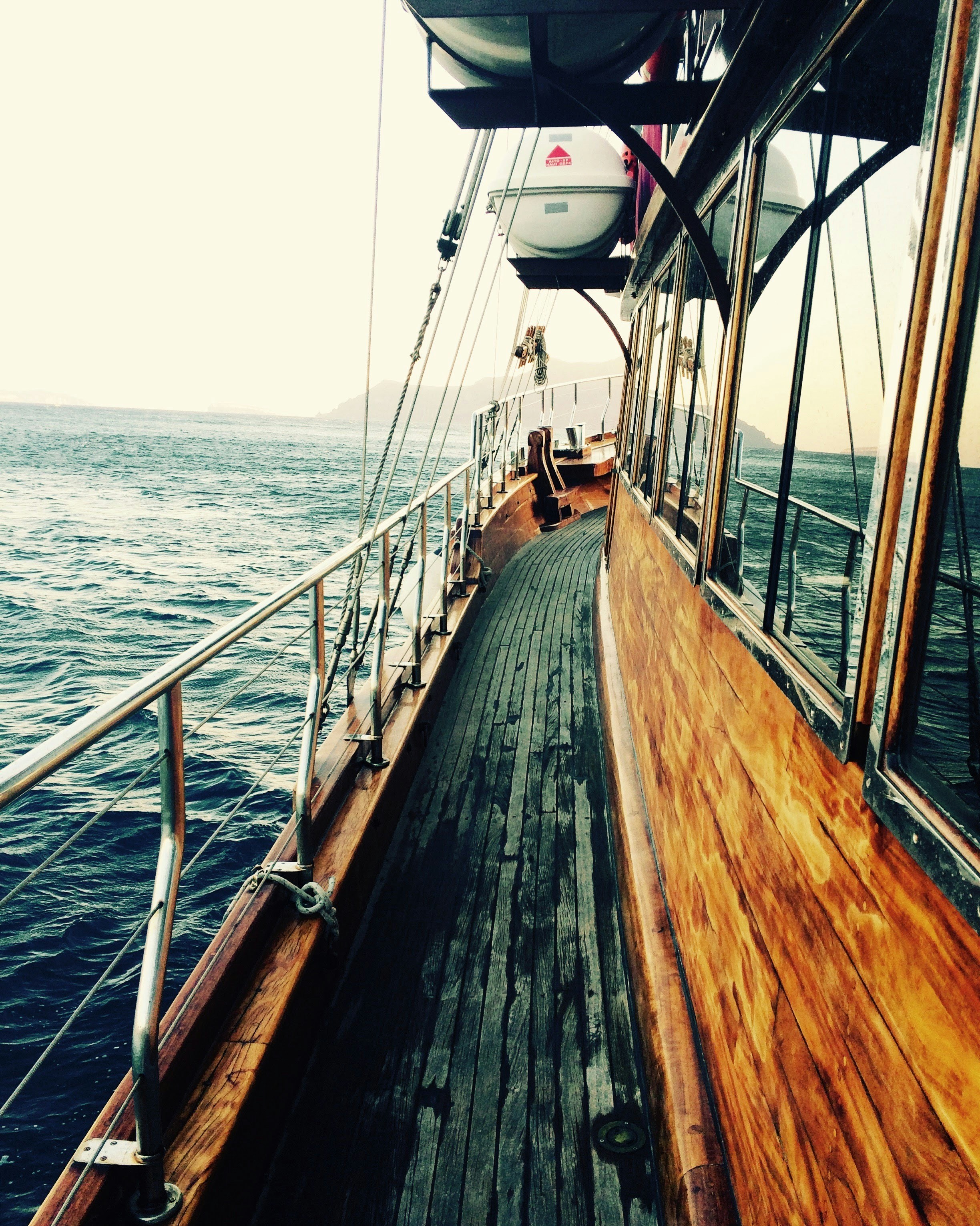 Teak Corridor to the Horizon: A Sailboat Deck Framed by Water and Glass
