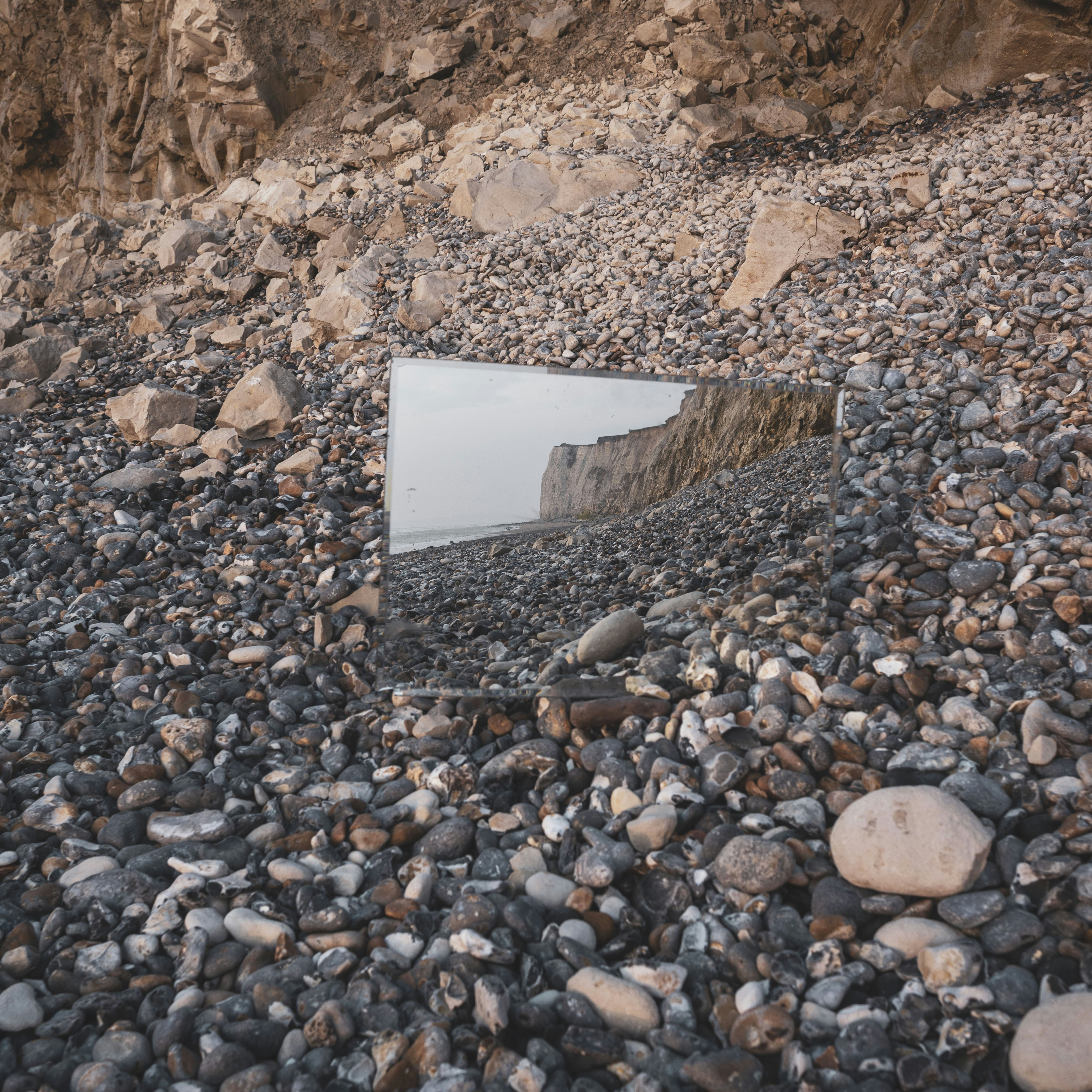 A mirror sitting on top of a rocky beach photo – Free France Image on ...
