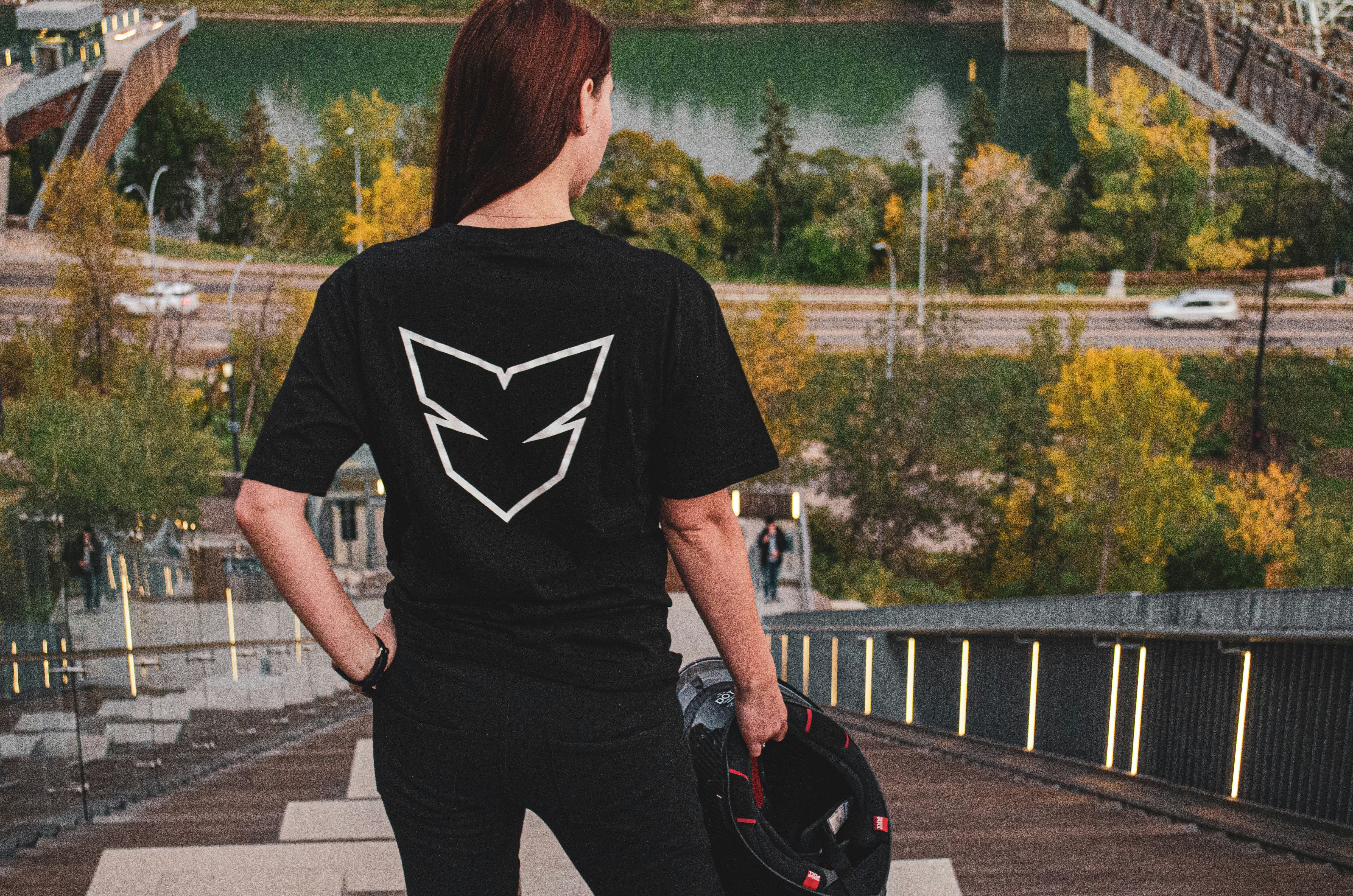 Urban Overlook: Figure in Black Pauses with Helmet in Hand