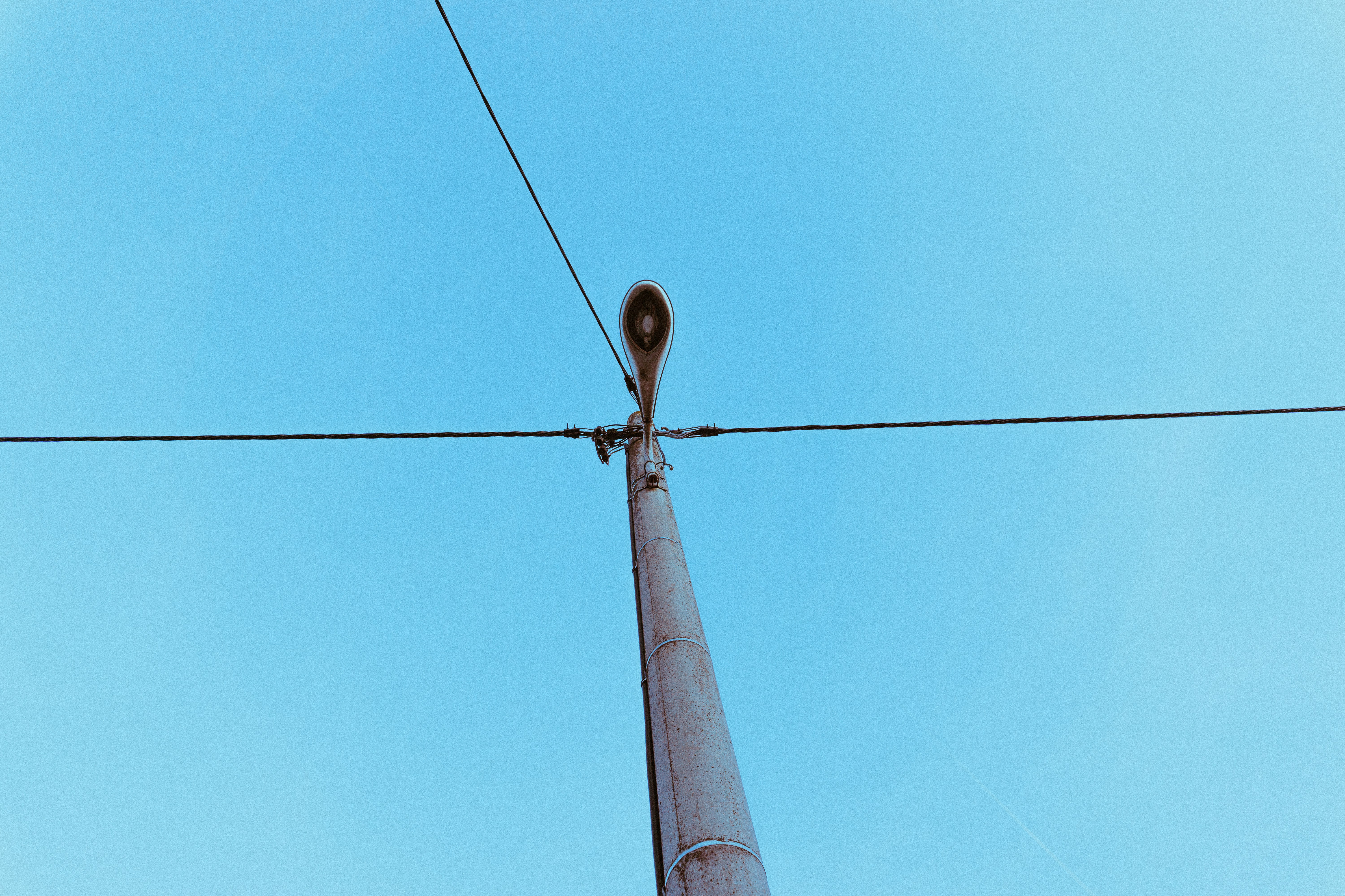 a street light on a wire with a blue sky in the background