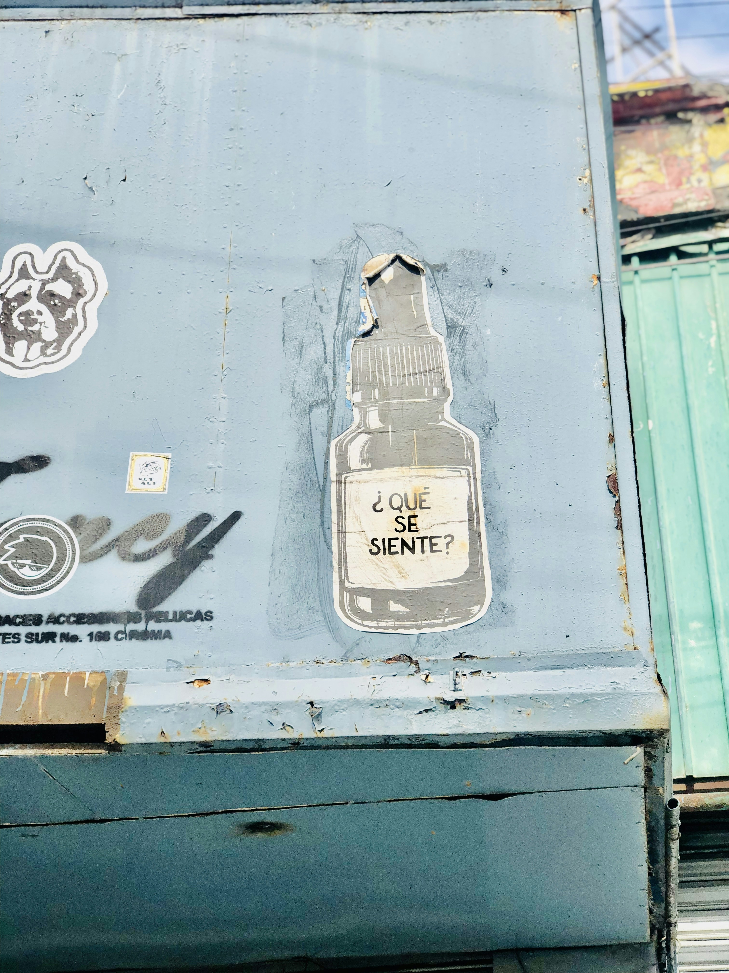 What Does It Feel Like? A Weathered Bottle Sticker on a Blue Industrial Panel