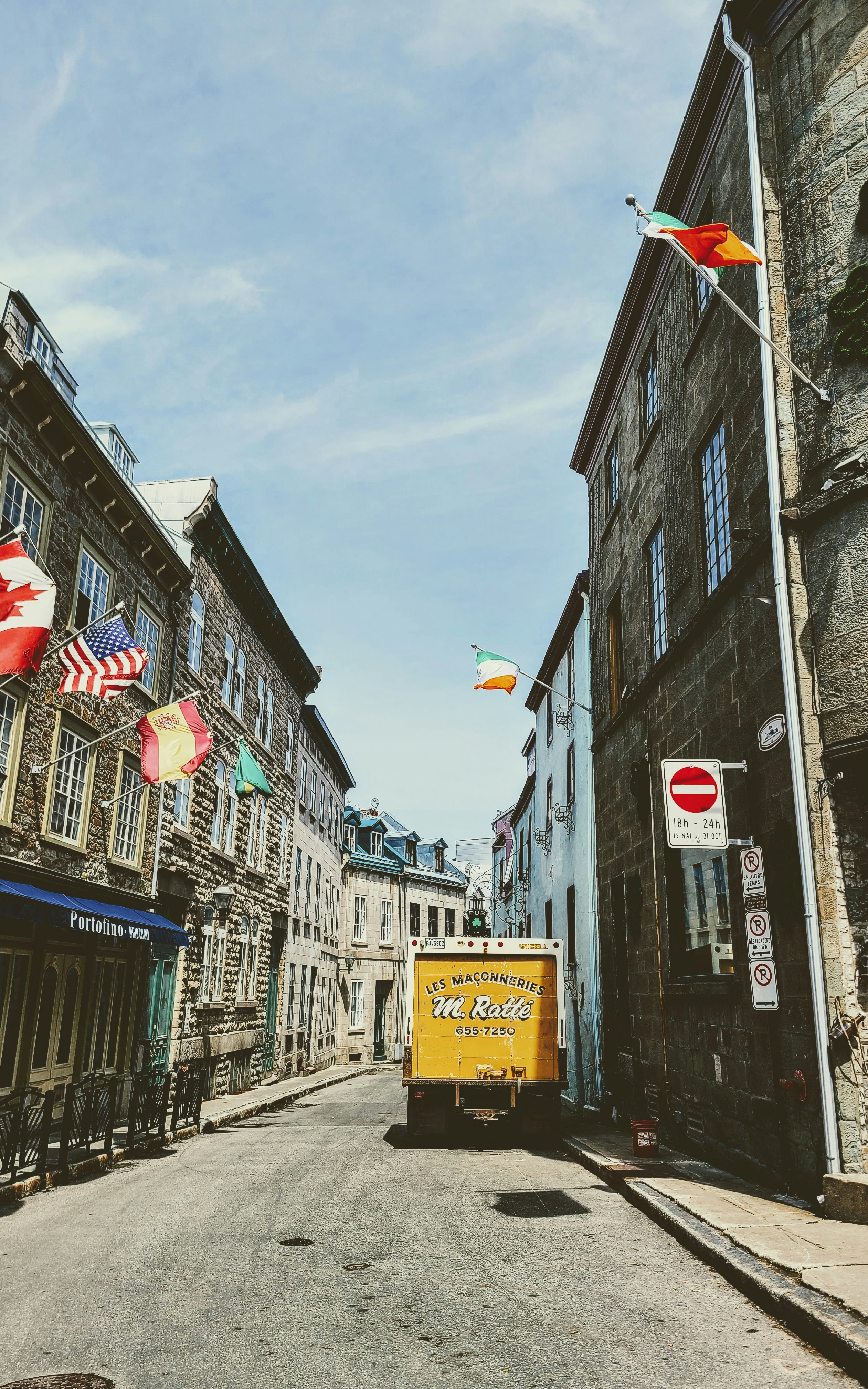 Flag-Lined Street: A Bright Yellow Truck Between Historic Facades