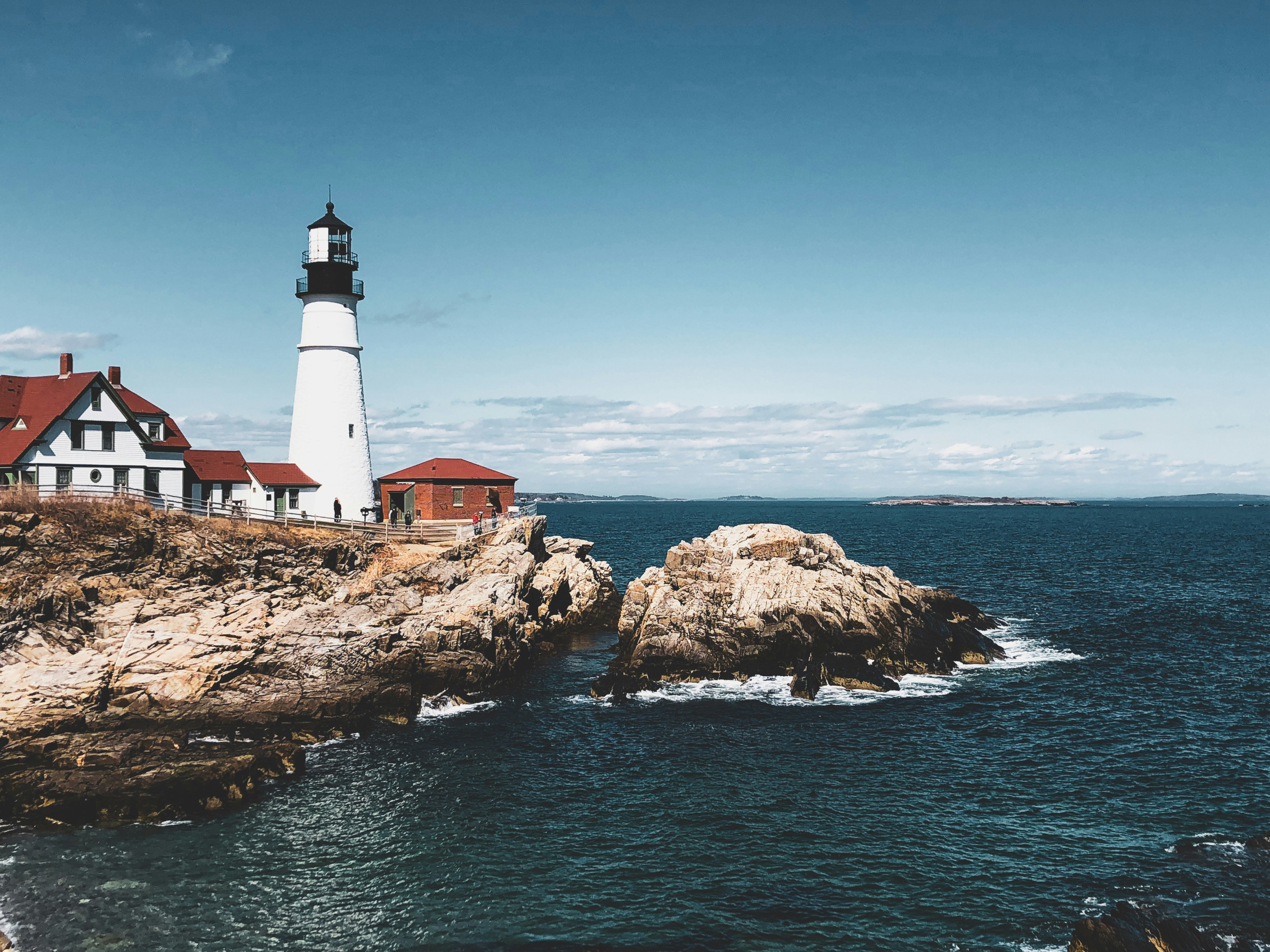 lighthouse in Maine  | a light house sitting on top of a cliff next to the ocean