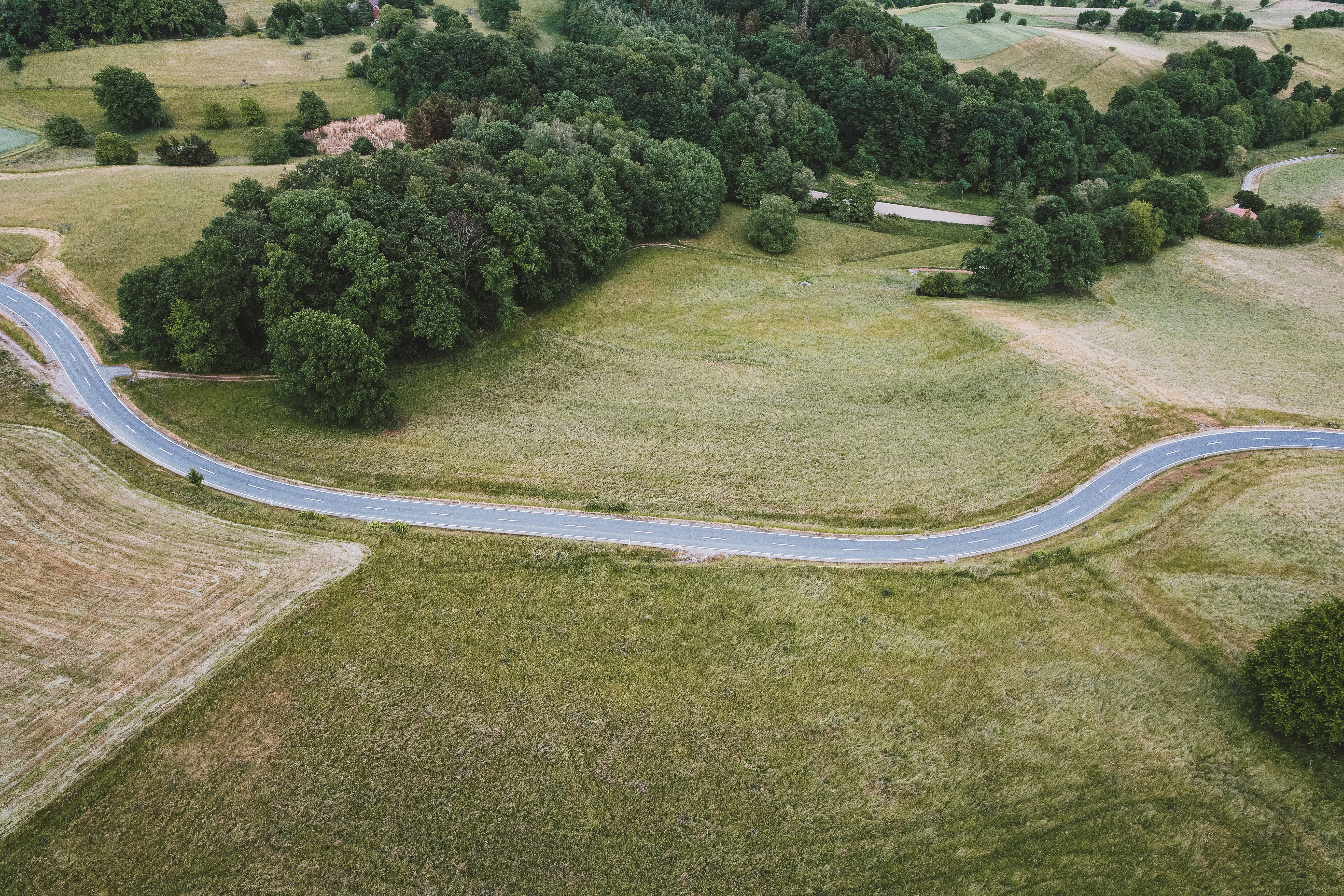 Serpentine Road Through Sunlit Fields: An Aerial Perspective