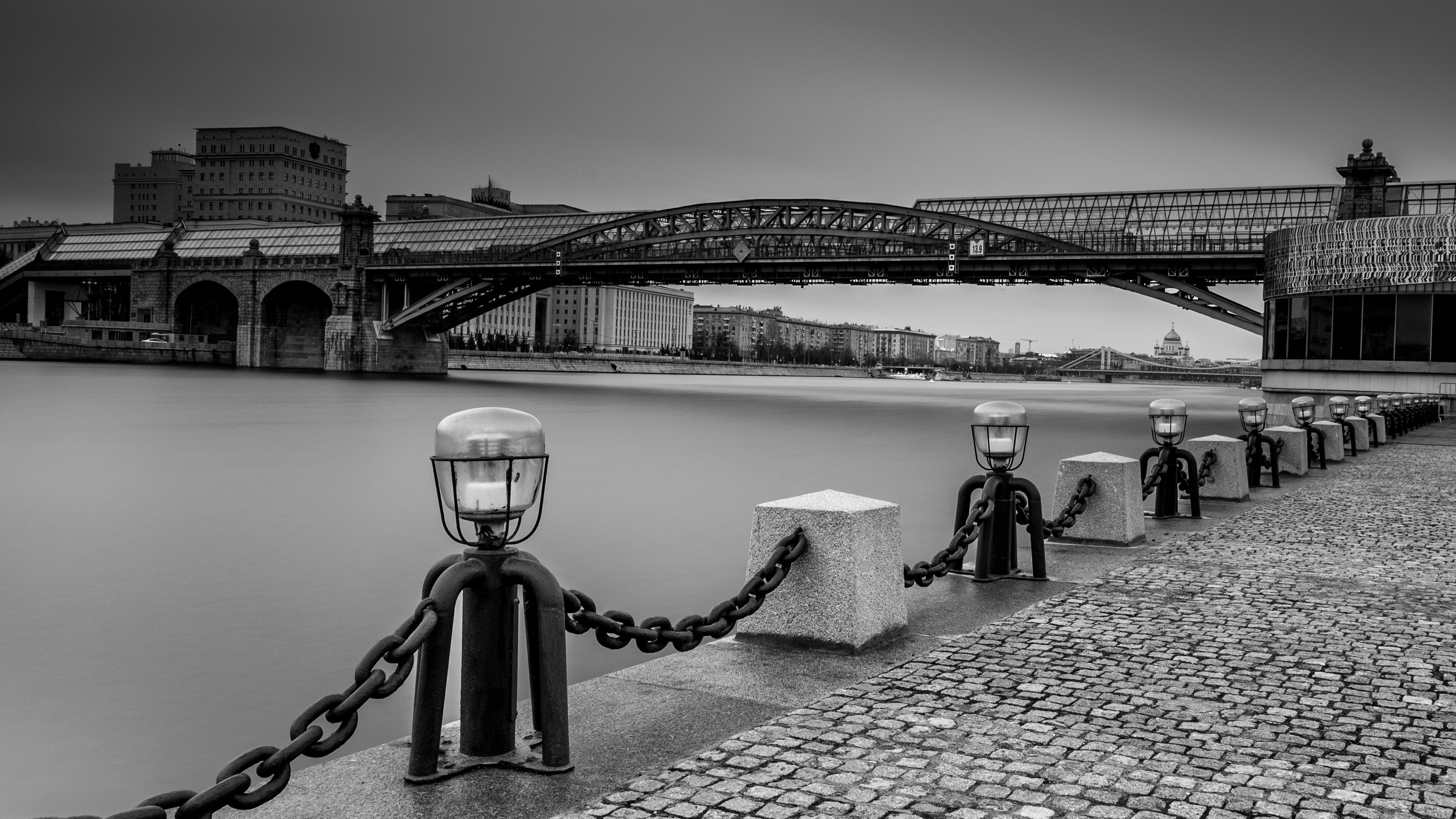 Lamps and Chains: A Quiet Riverfront Under Steel Arches