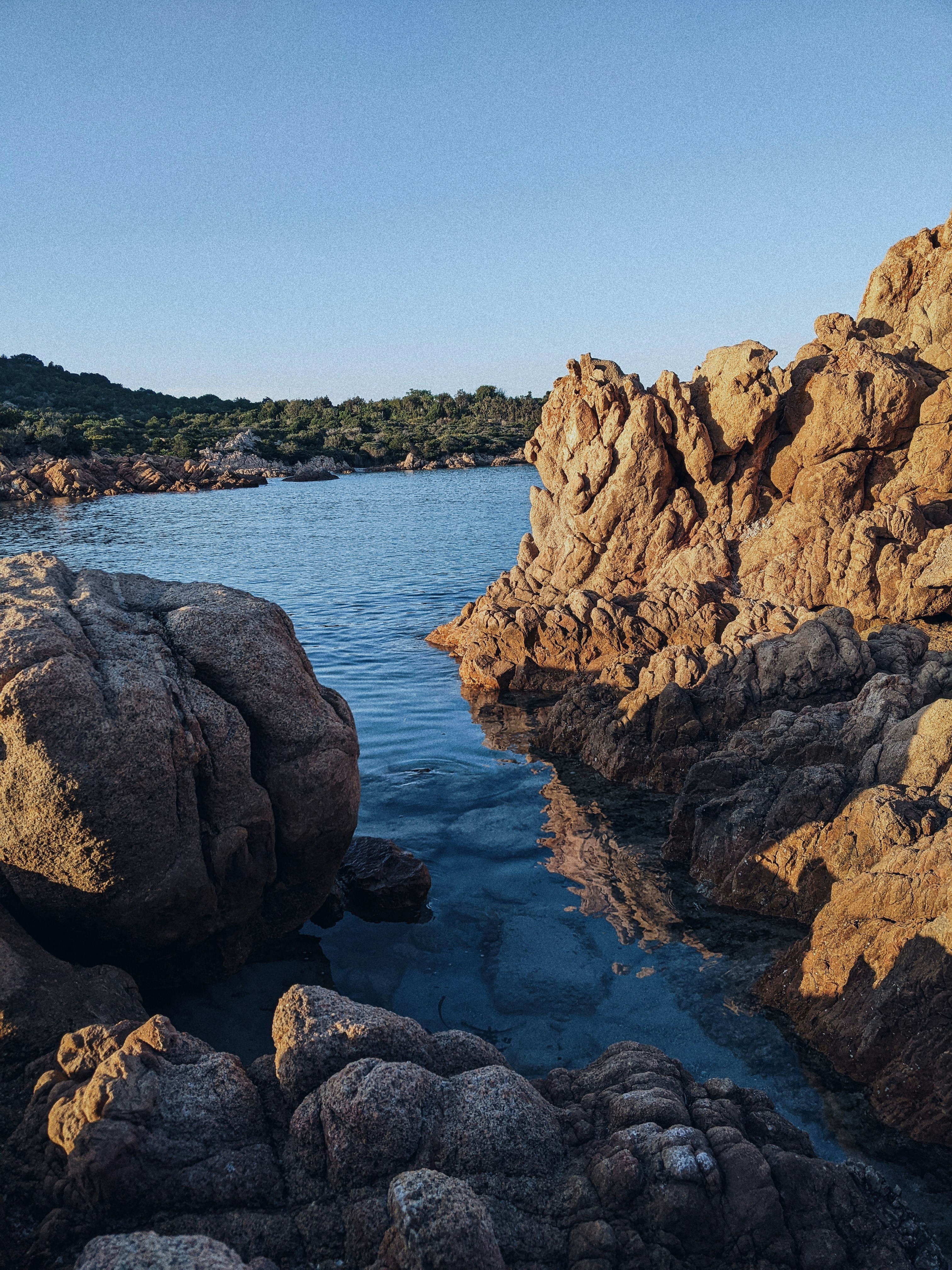 A body of water surrounded by large rocks photo – Free Spiaggia del ...