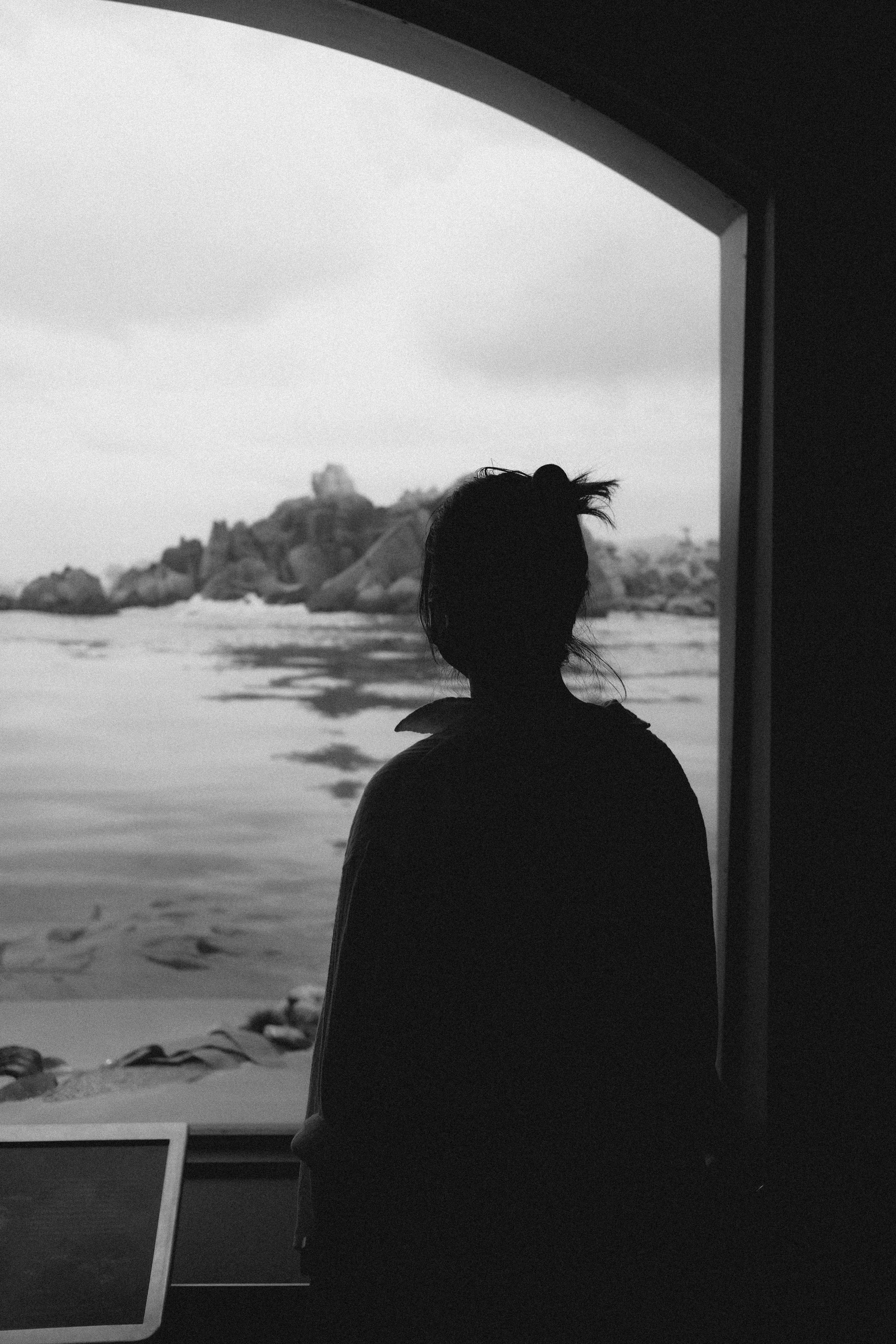 Foto Una persona mirando por una ventana a un cuerpo de agua – Imagen ...