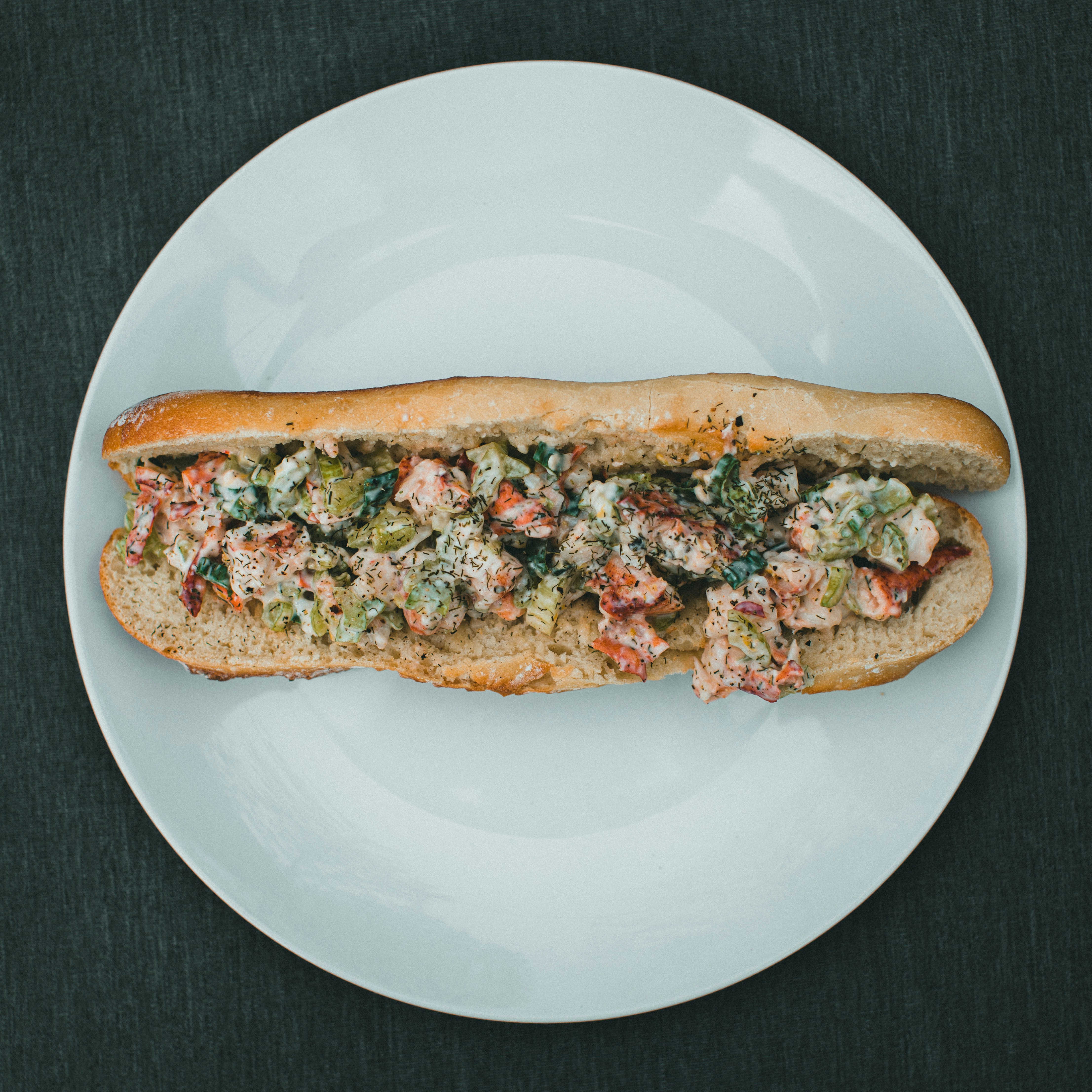 Une assiette blanche surmontée d’un sandwich sur le dessus d’une table ...