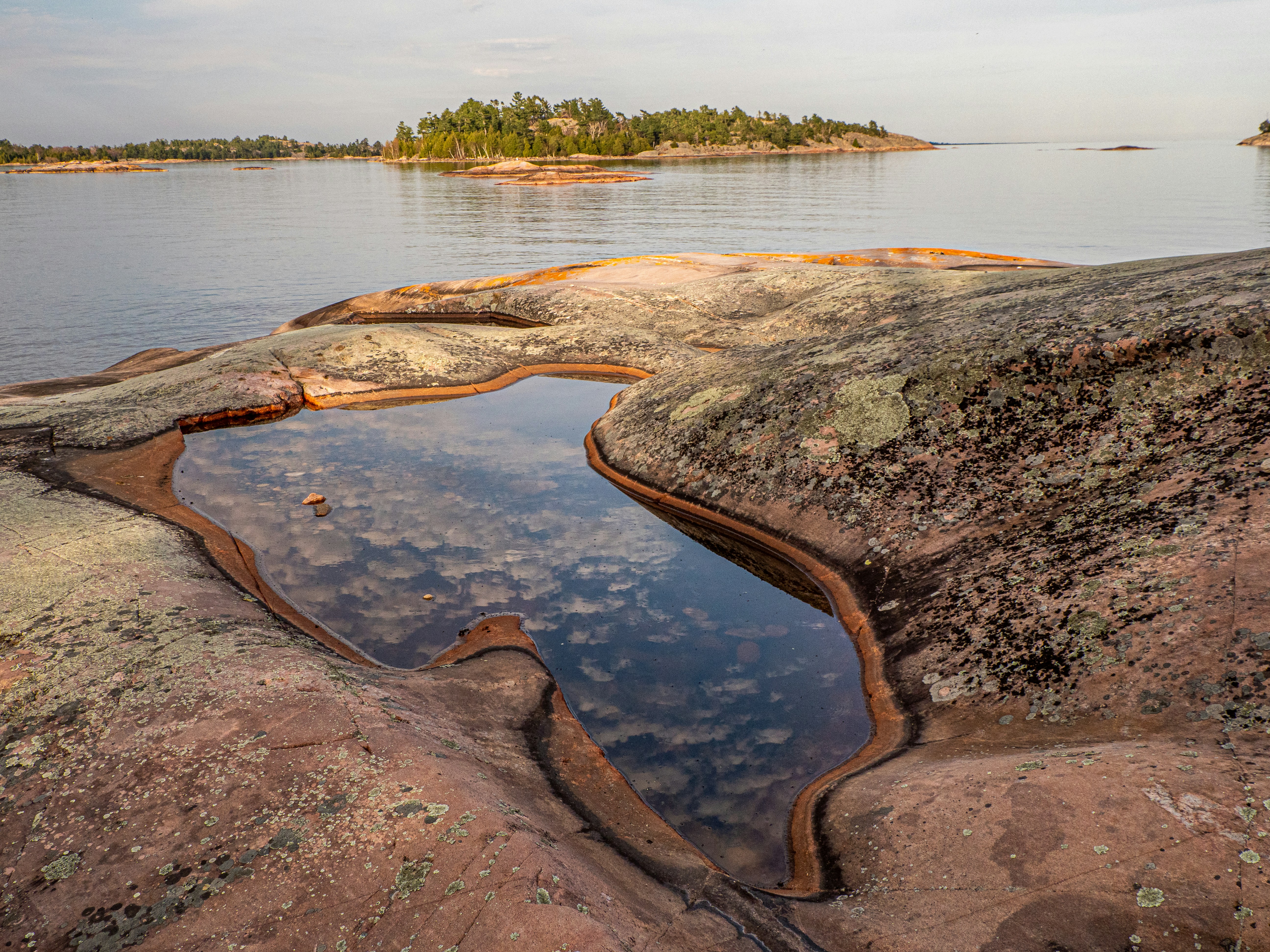 A body of water surrounded by large rocks photo – Free Land Image on ...