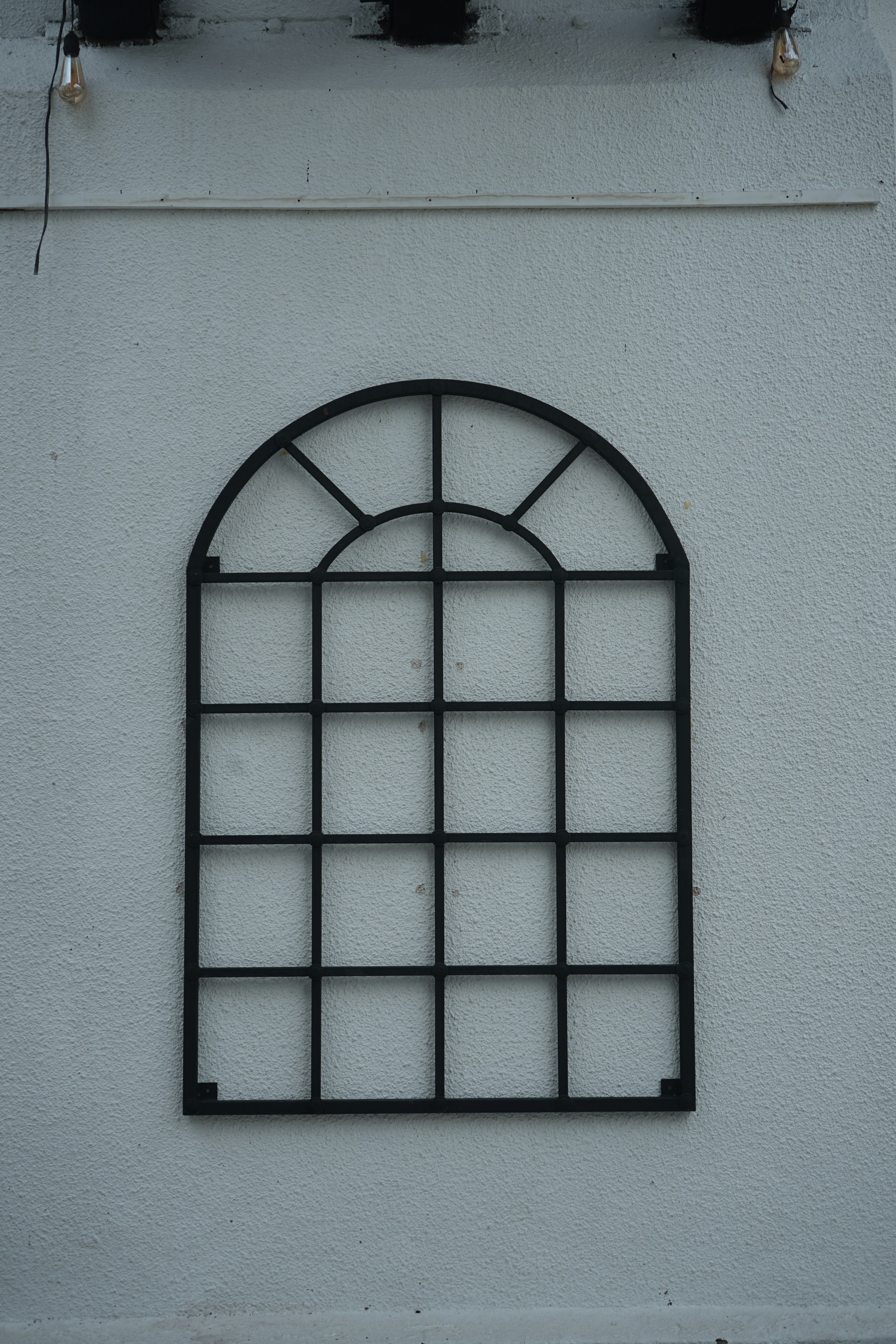 Arched Iron Grid Framed by a Minimal White Facade