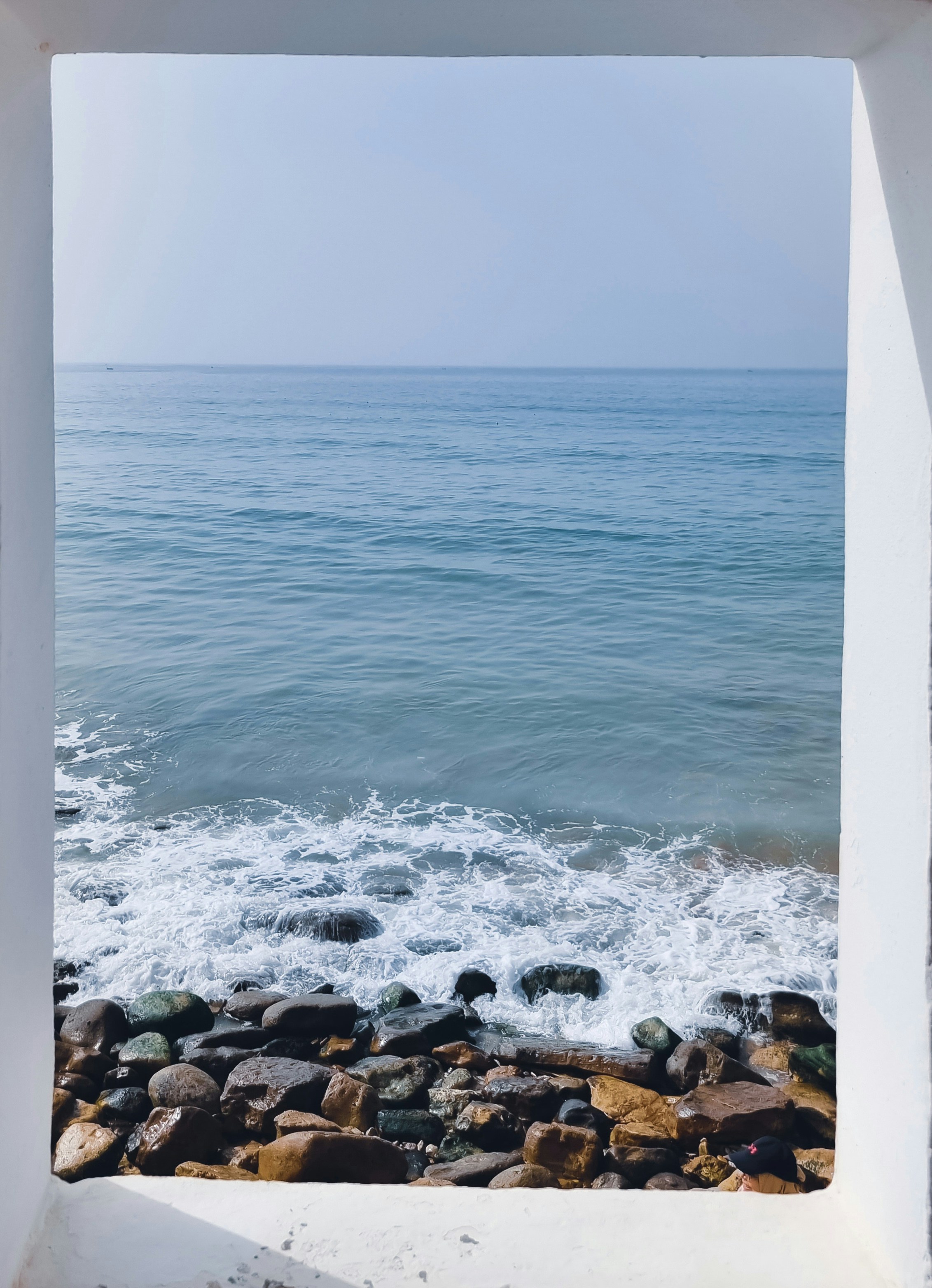 Sea Framed by White Archway: Pebbles, Wavelets, and Horizon
