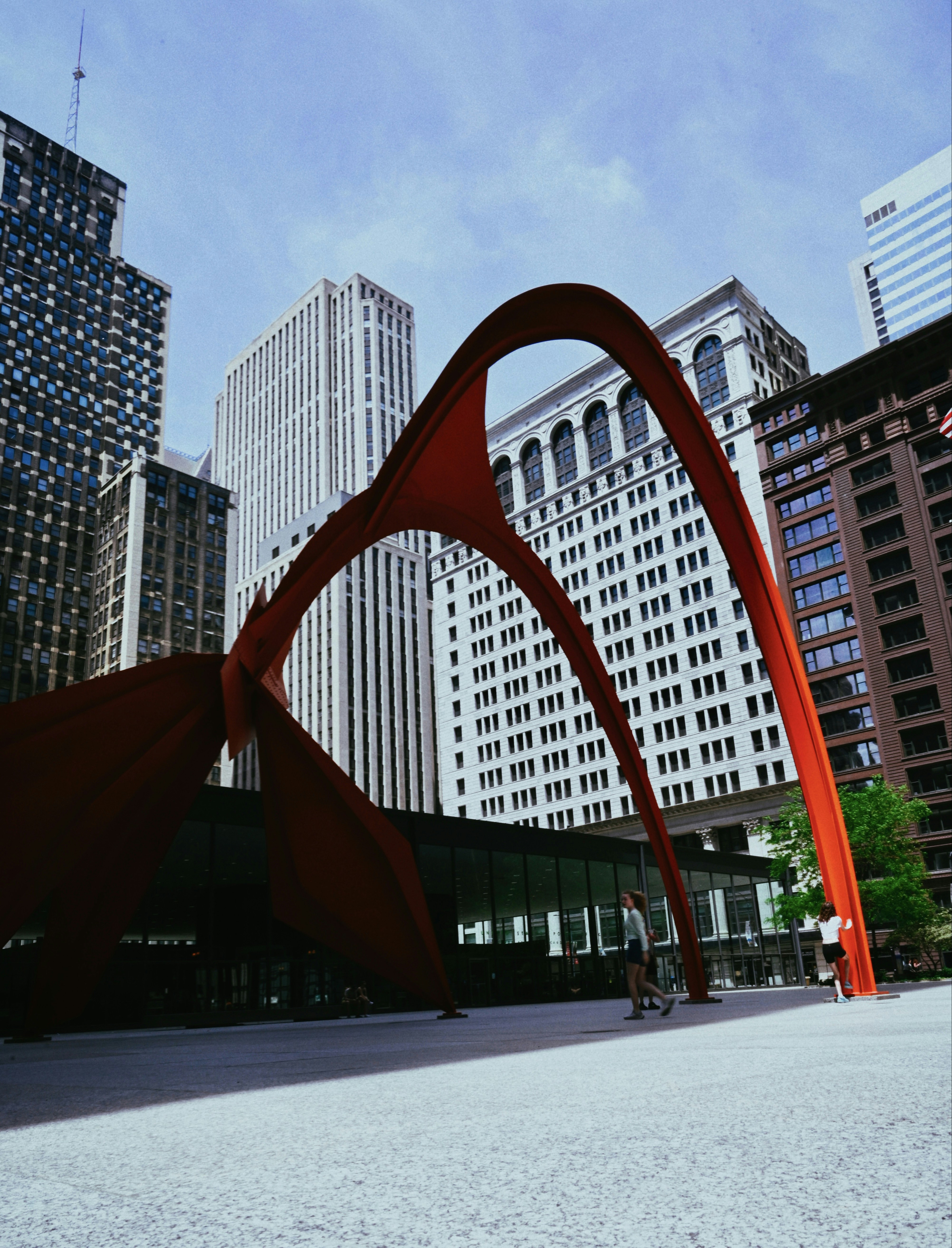 A large red sculpture in front of a large building photo – Free ...