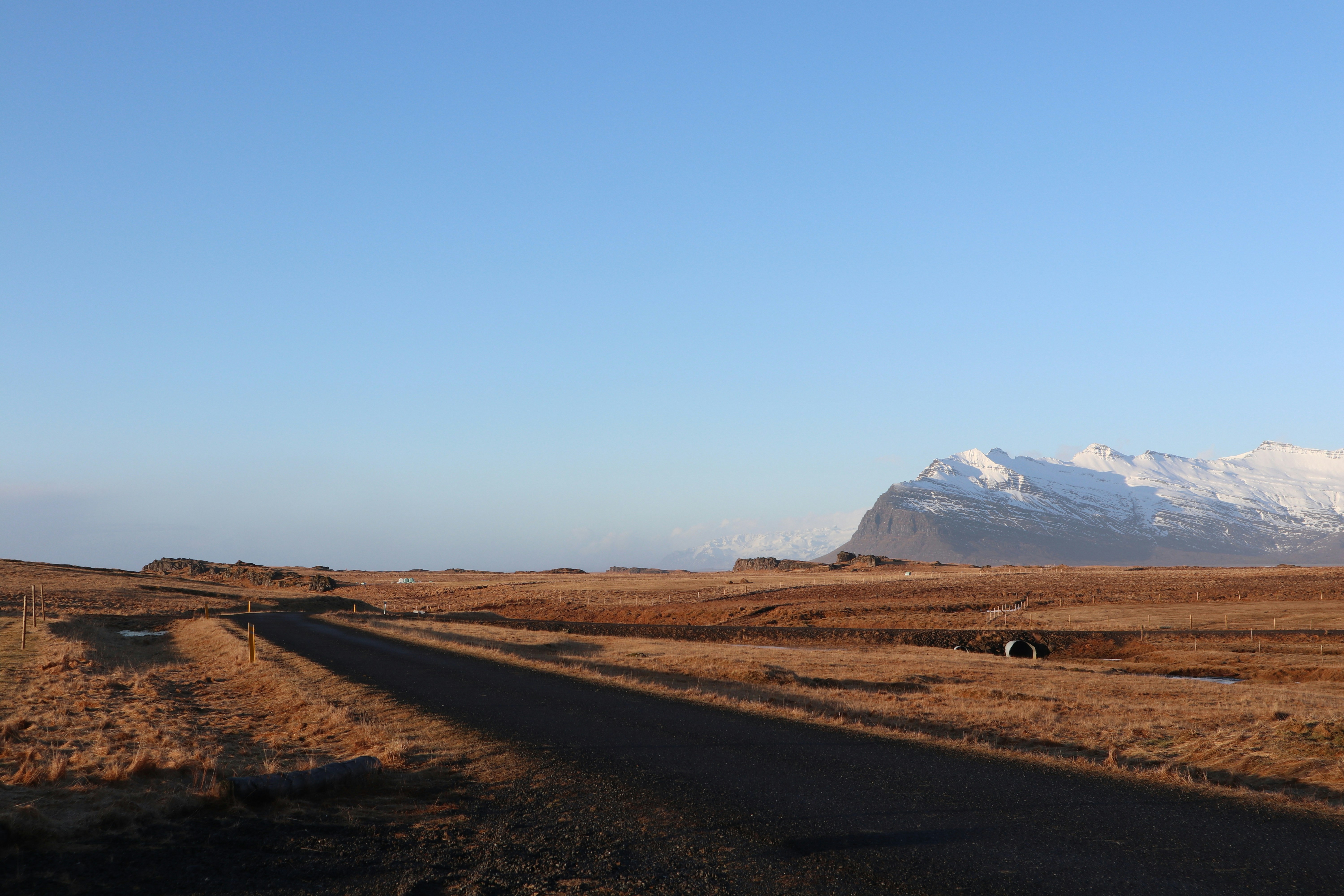 Gravel Path to a Snow-Capped Horizon under a Pristine Blue Sky