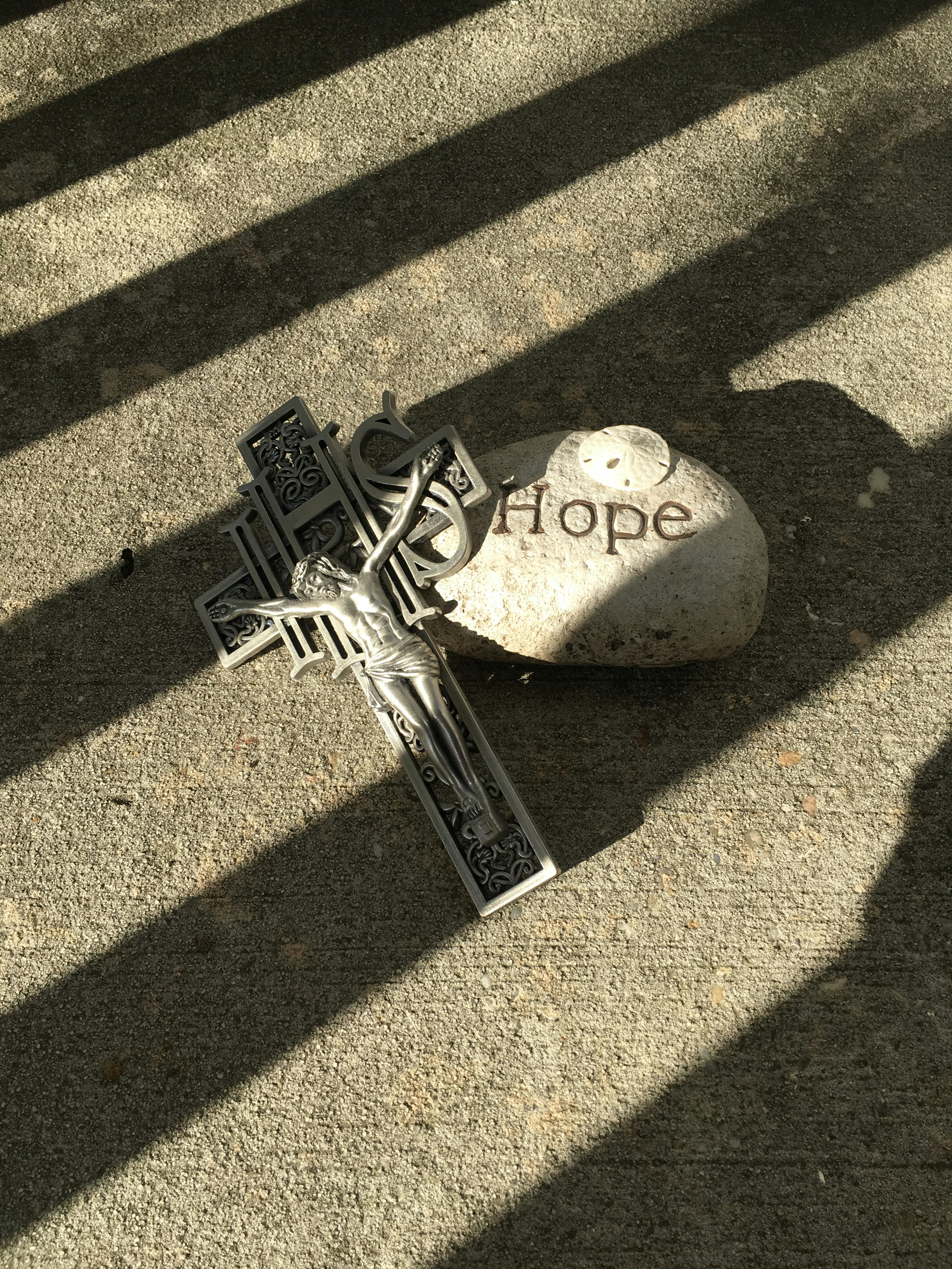 A cross laying on the ground next to a rock photo – Free Religious ...