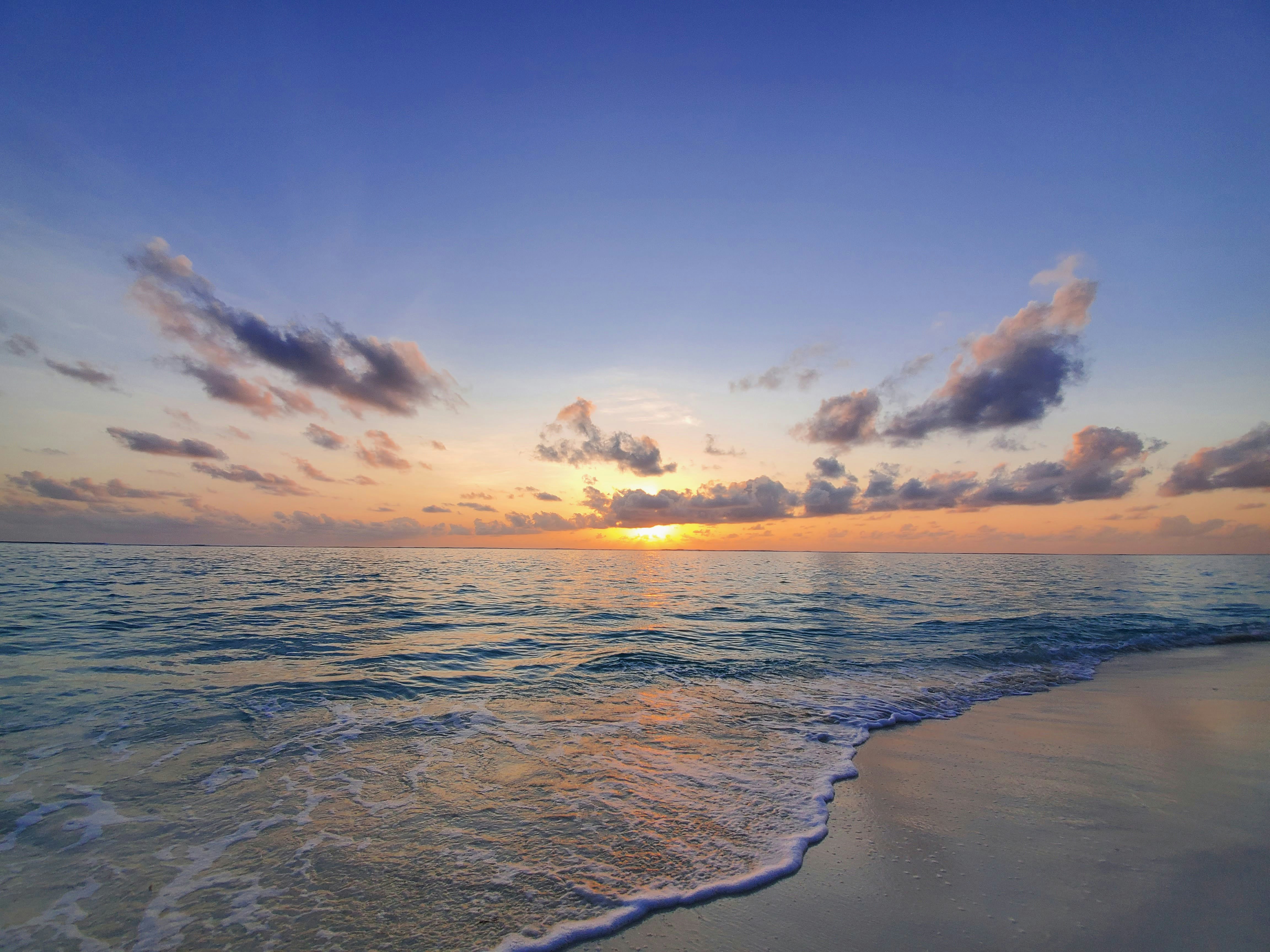 The sun is setting over the water at the beach photo – Free Maldives ...
