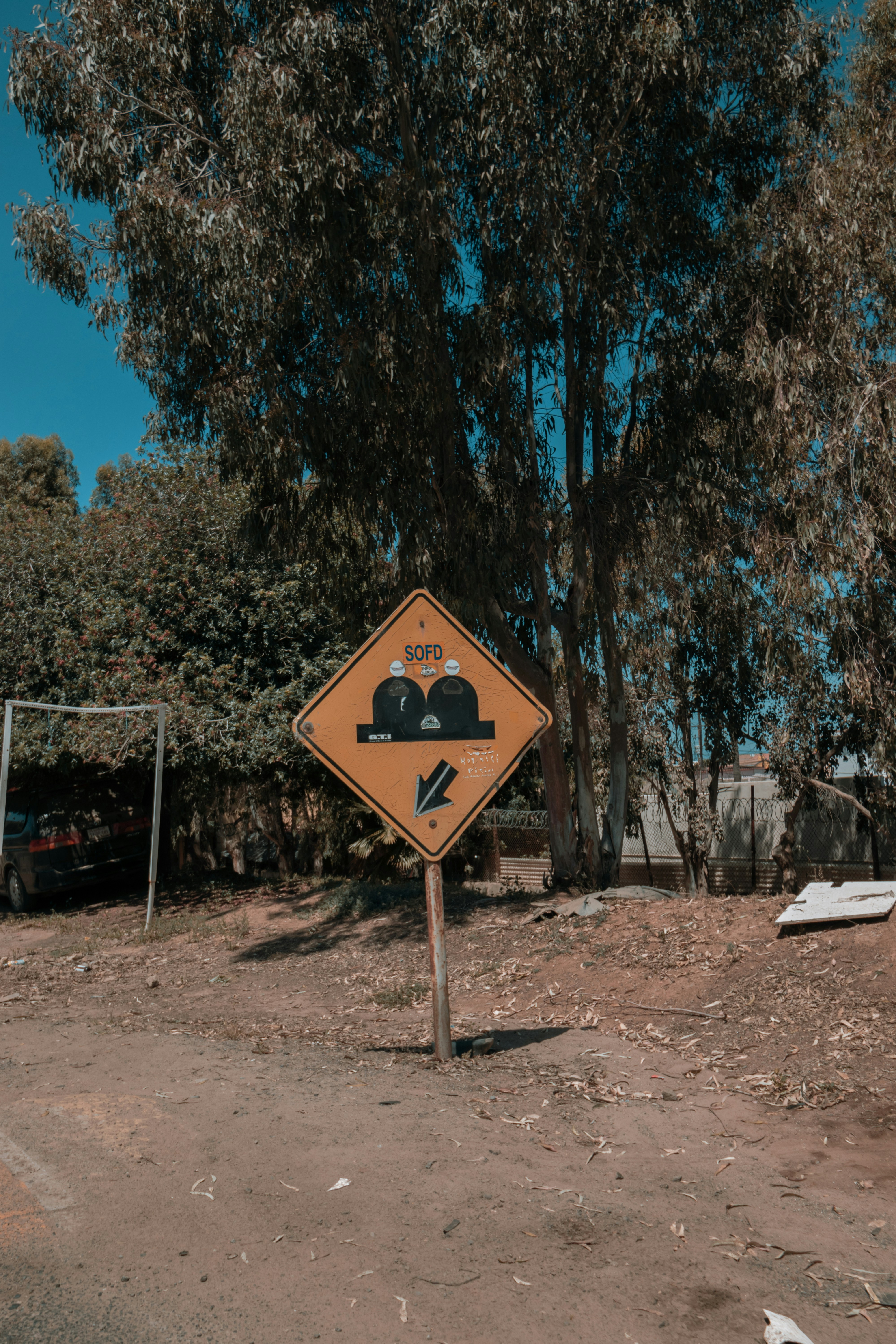 Canopy Warning: A Lone Yellow Sign on a Dusty Road