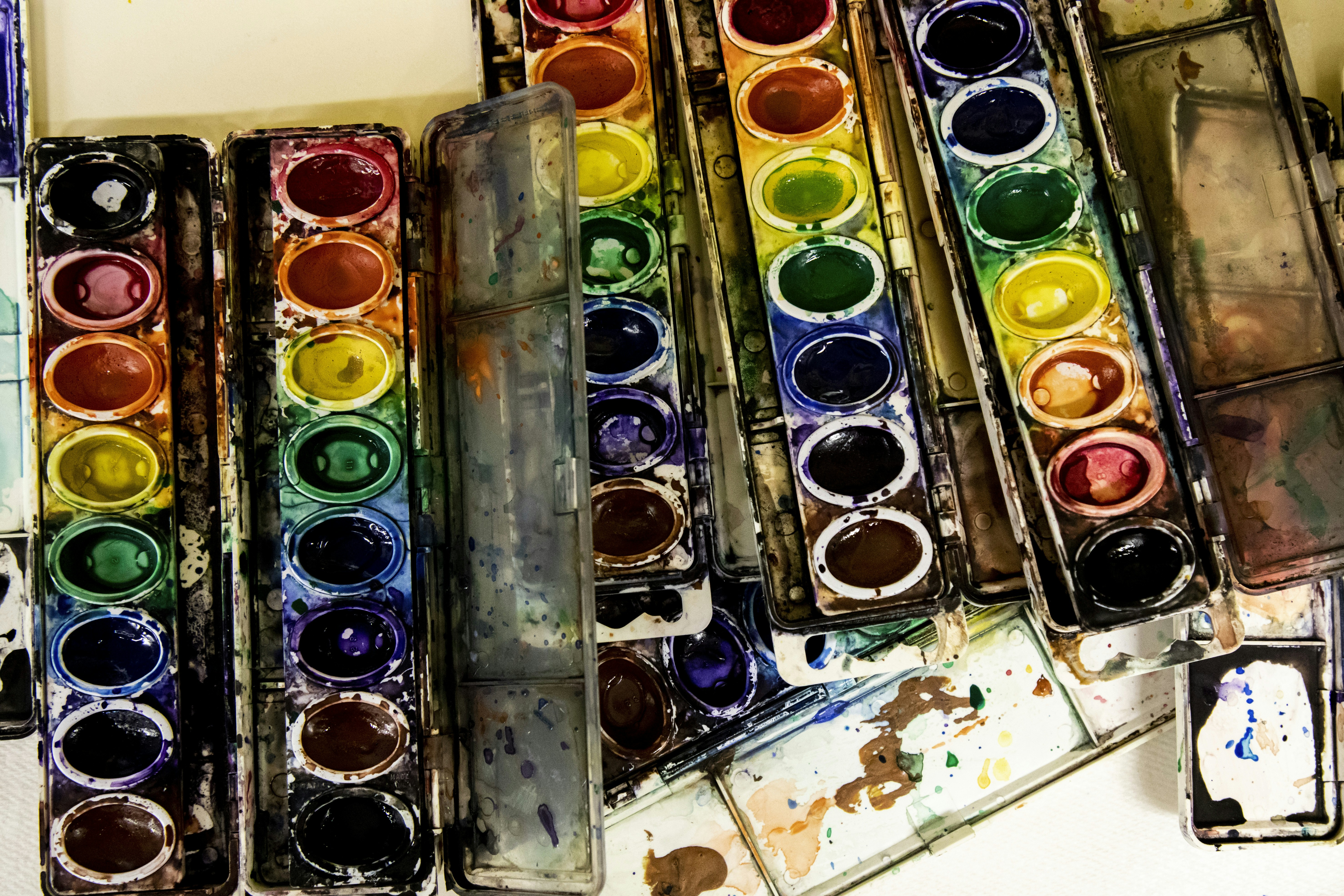 Open watercolor palettes with vibrant, mixed hues reflecting artistic creativity.