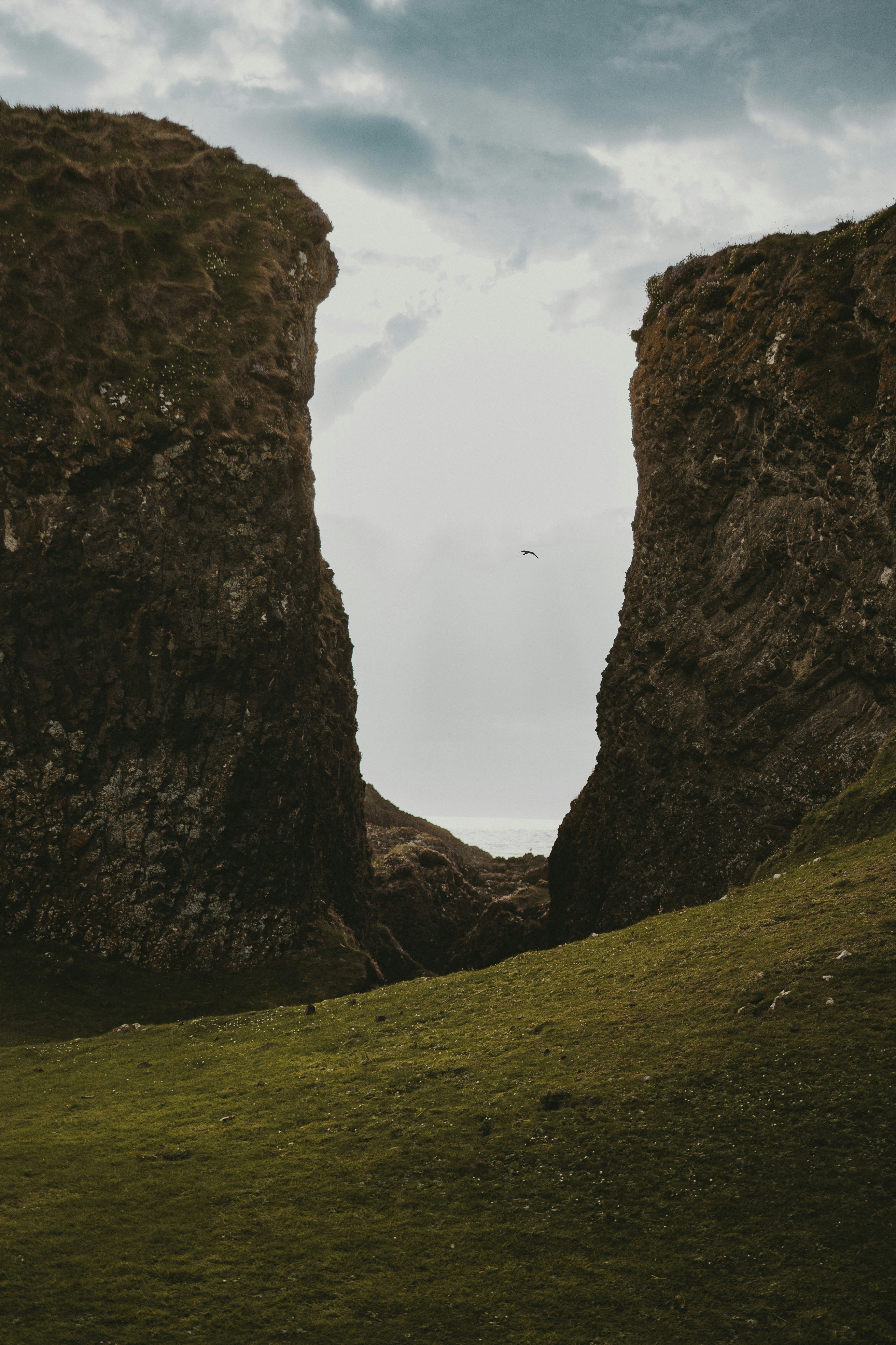 Natural rock formations frame a distant view of the sky, hinting at the vastness beyond. The grassy foreground adds depth to the scene.