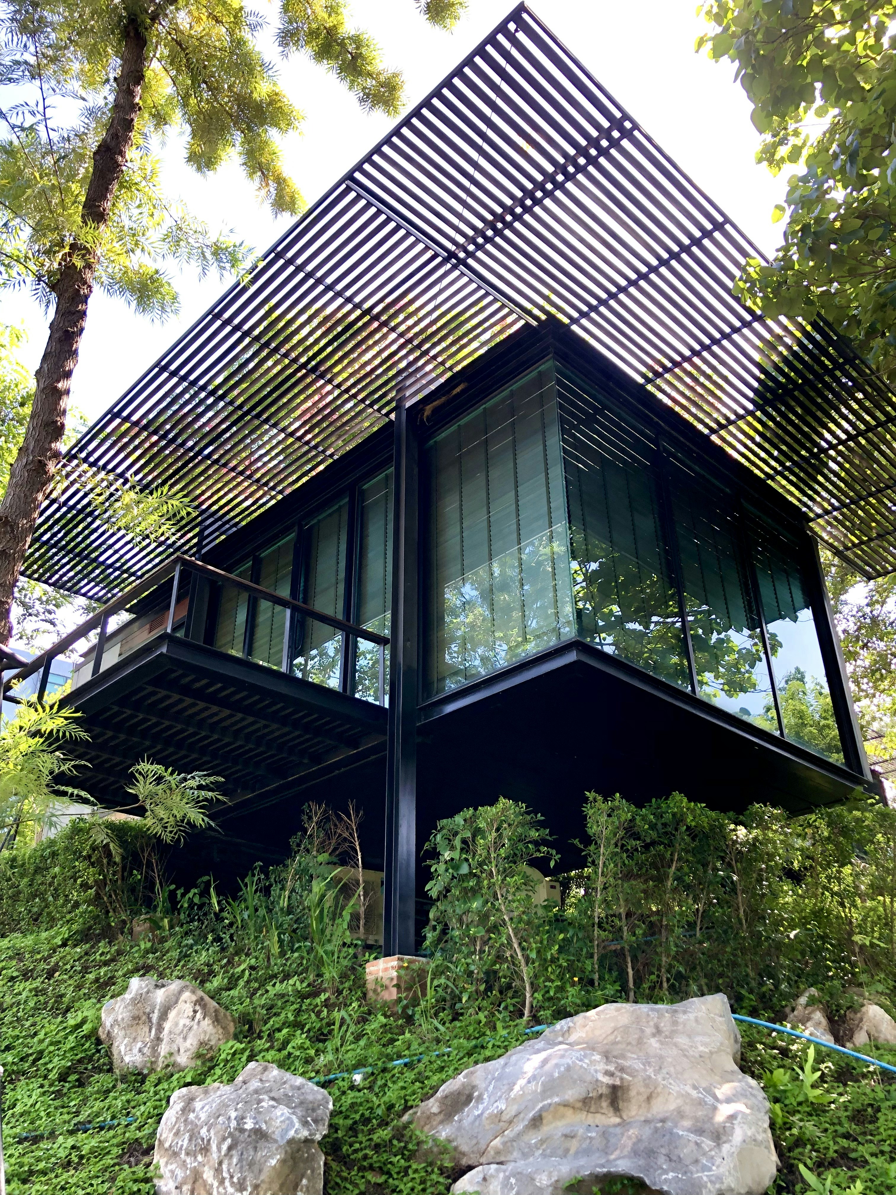 Louvred Glass Pavilion Rising Over a Rock Garden