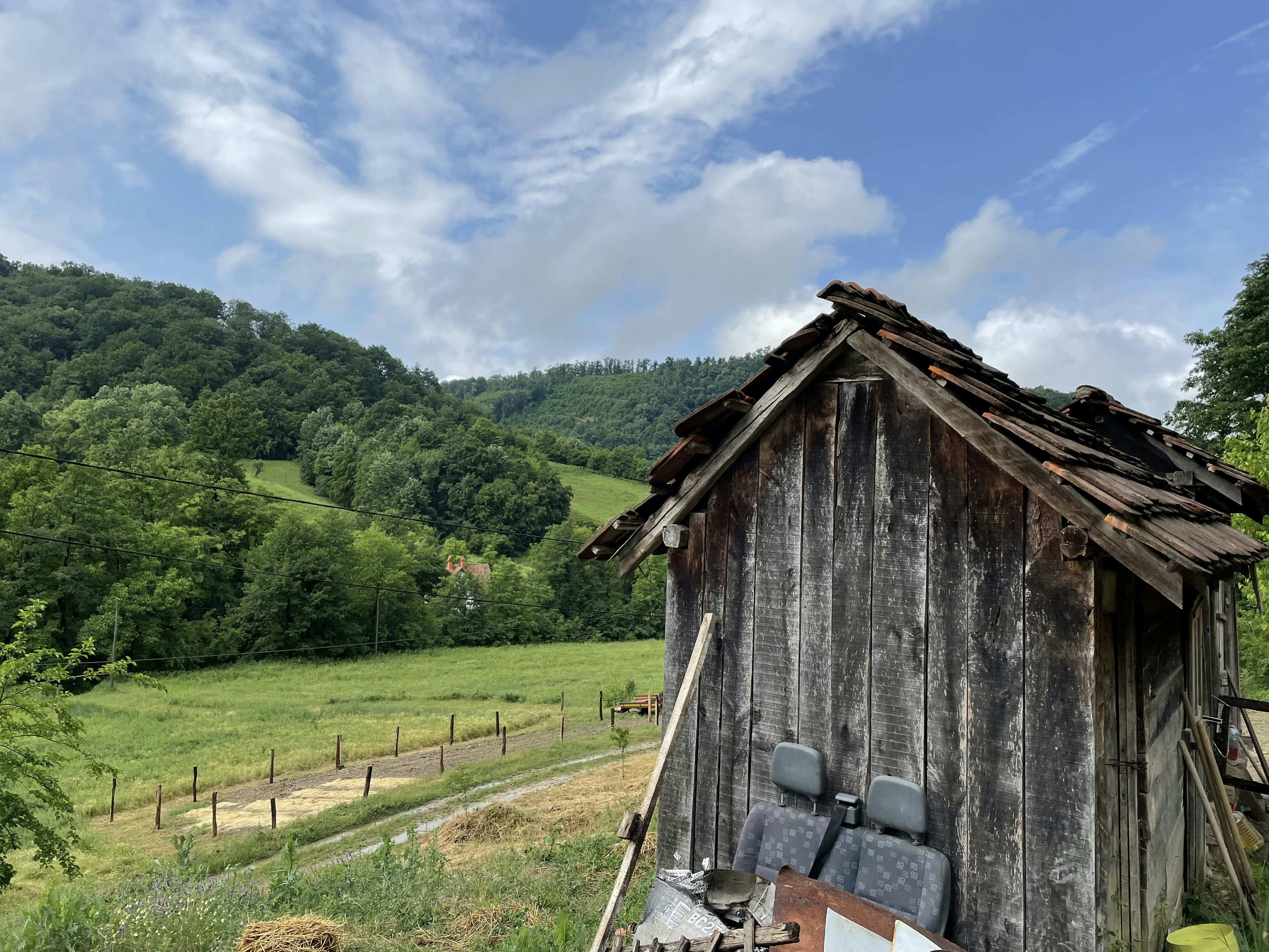 Weathered Shed Anchors a Quiet Green Valley Beneath a Broad Blue Sky