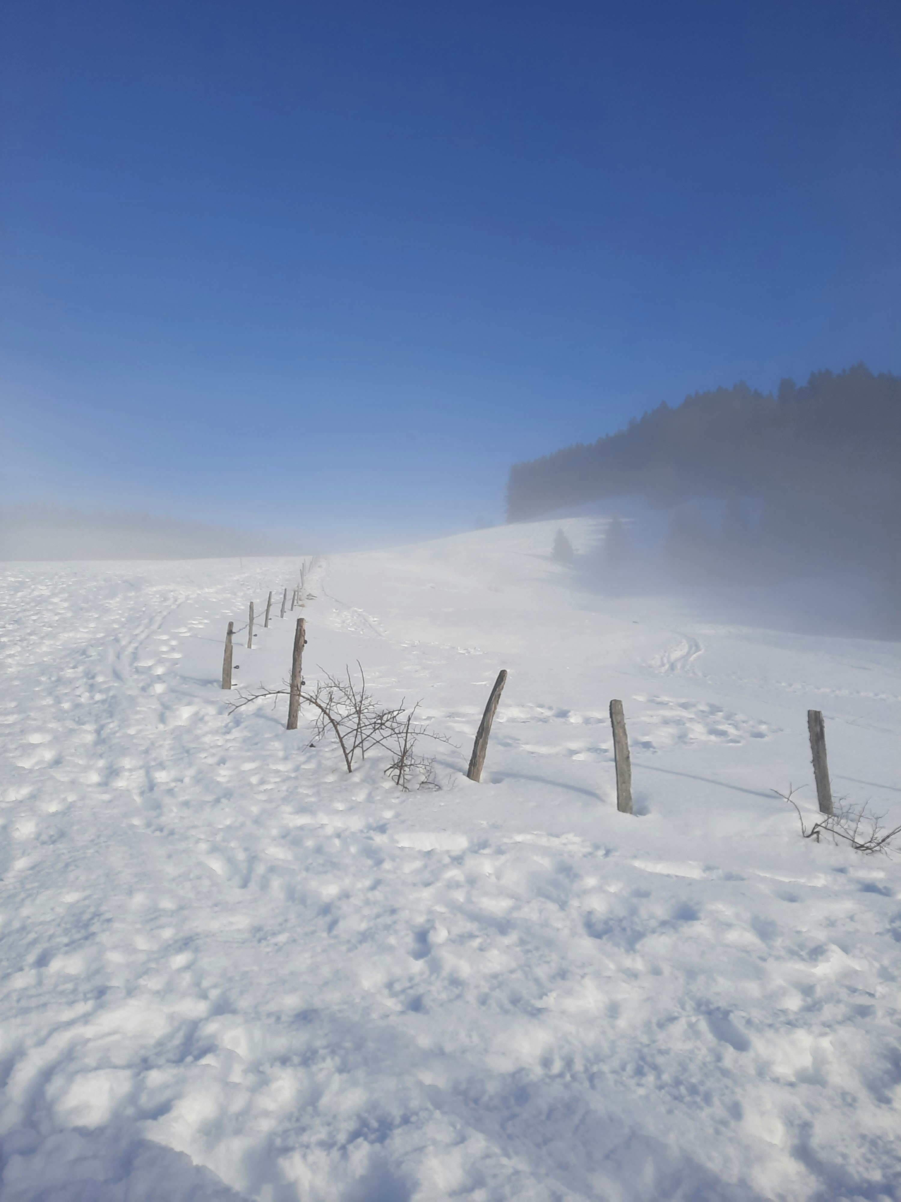 A snow covered field with a fence and a hill in the background photo ...