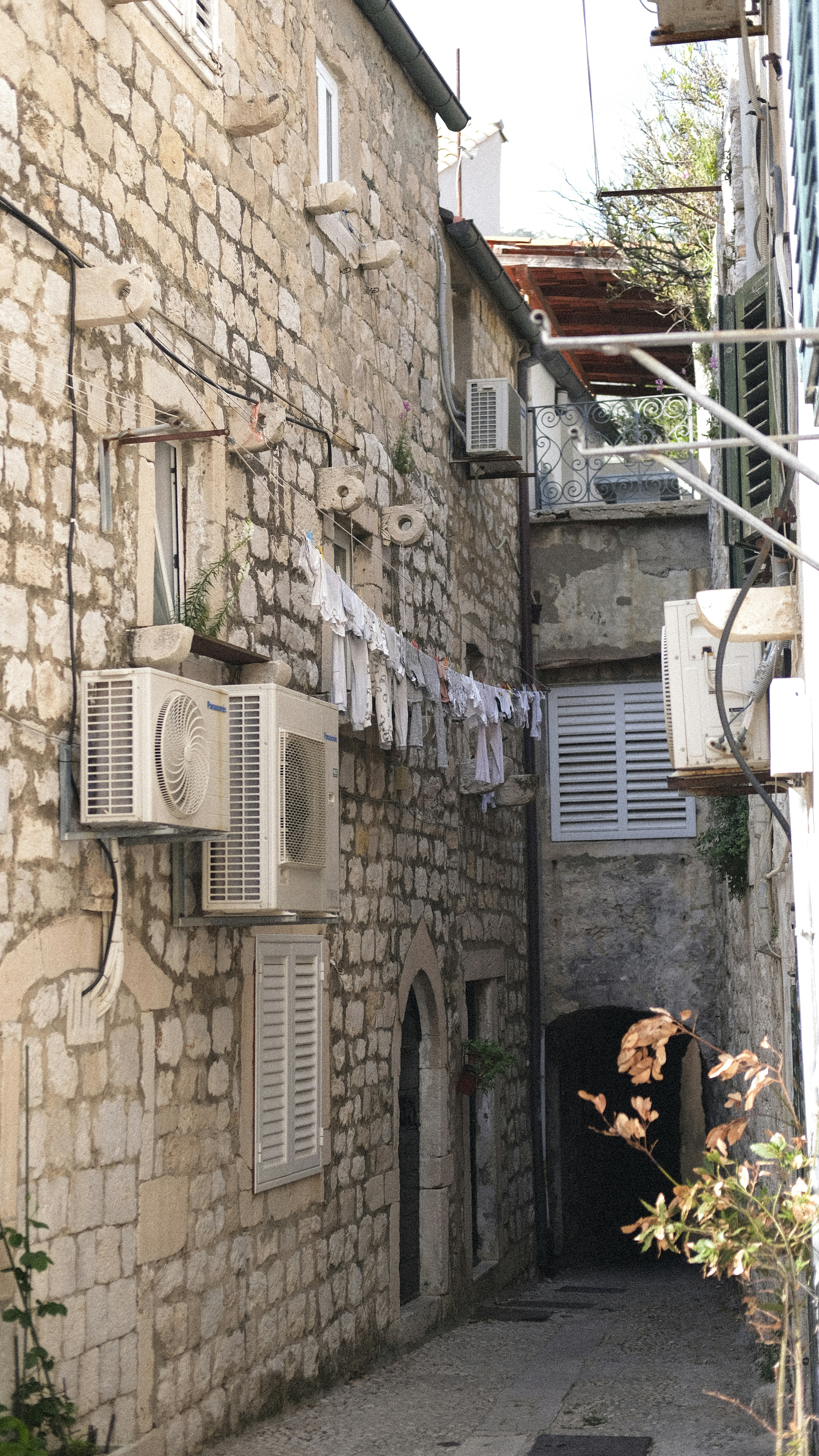 Laundry Lines over a Sunlit Stone Alley Ending in a Shadowed Arch