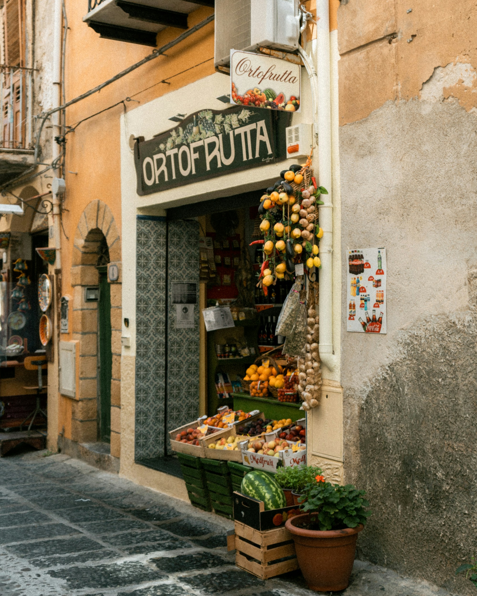Ortofrutta: A Sunlit Fruit Shop Nestled Along a Narrow Italian Street